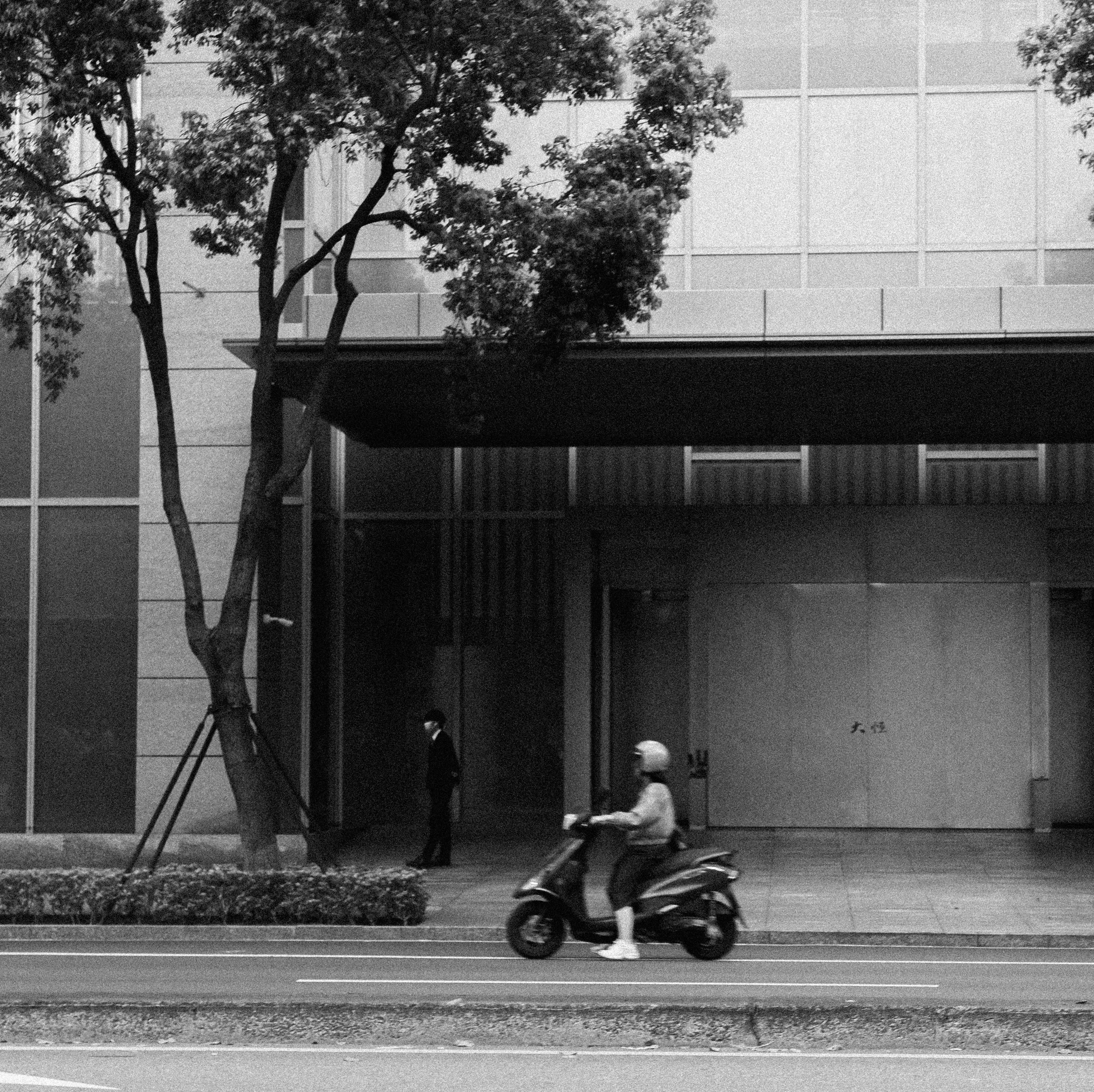 Motorcyclist and passerby at a modern façade