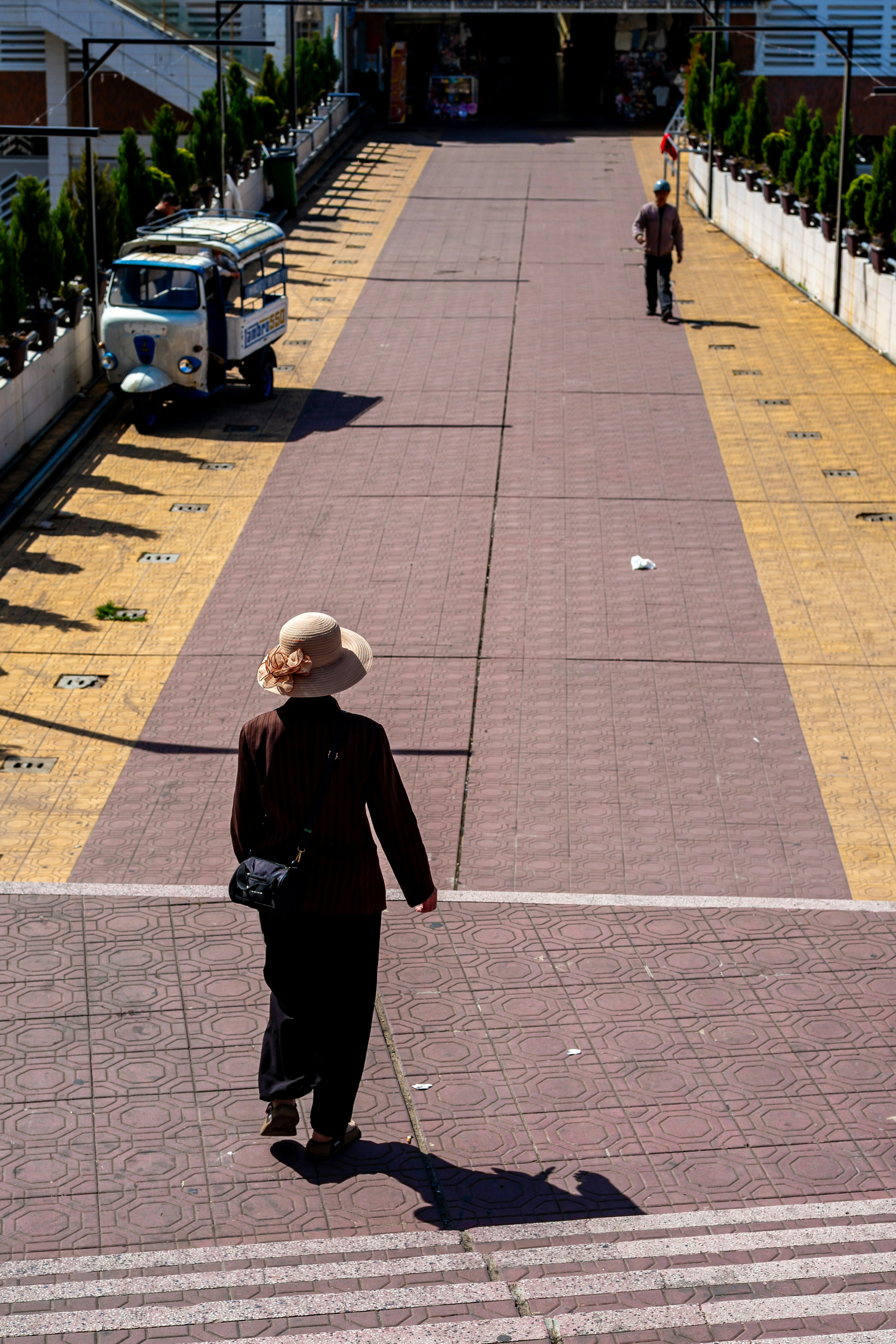 Pedestrian Crossing the Tiled Plaza: A Quiet Moment at the Walkway