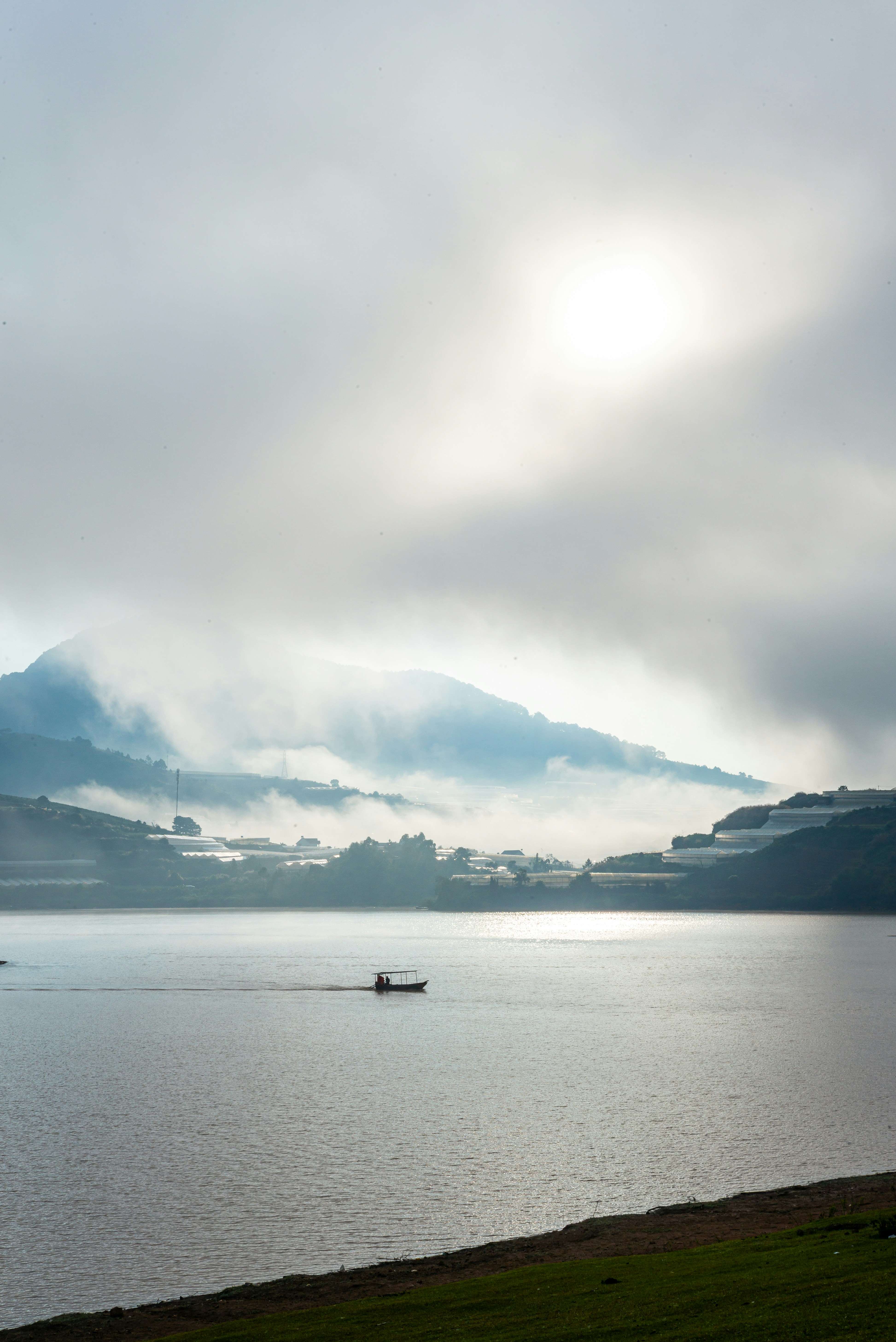 Mist over the Lake: A Quiet Boat Amid Shrouded Hills