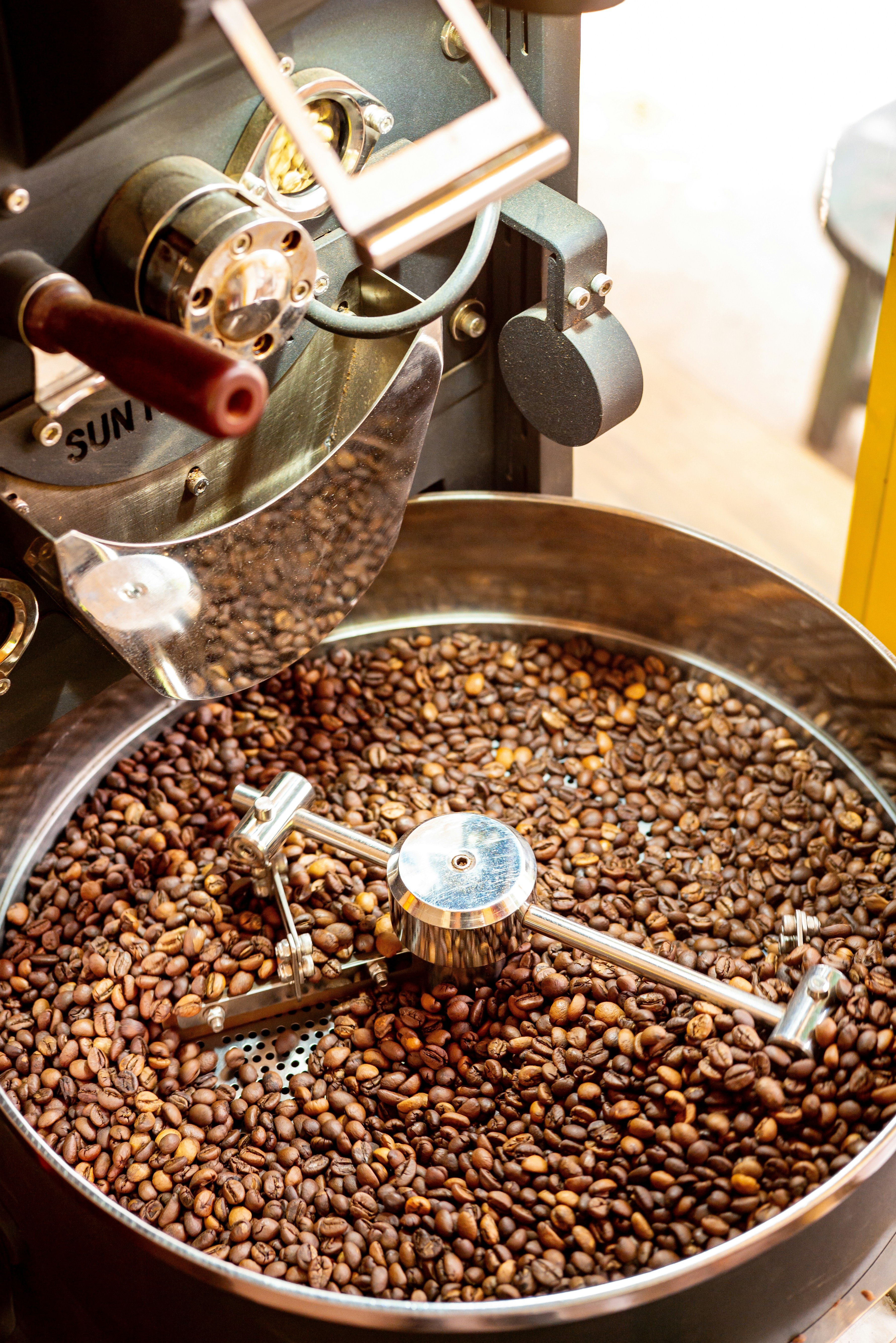 Coffee roaster's heart: roasted beans swirl beneath the hand-cranked mechanism