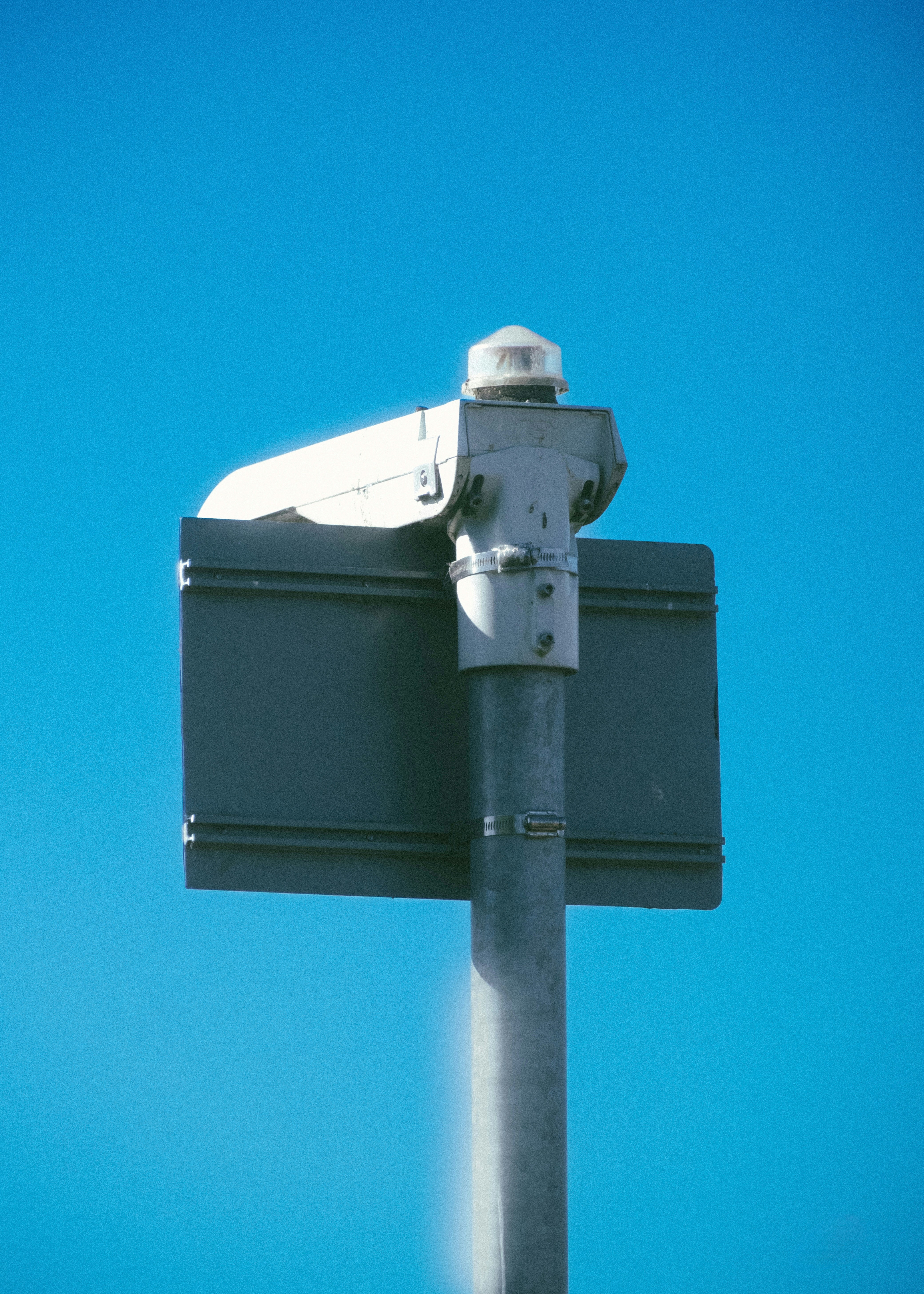 Close-up of a Utility Surveillance Camera Against a Crisp Blue Sky
