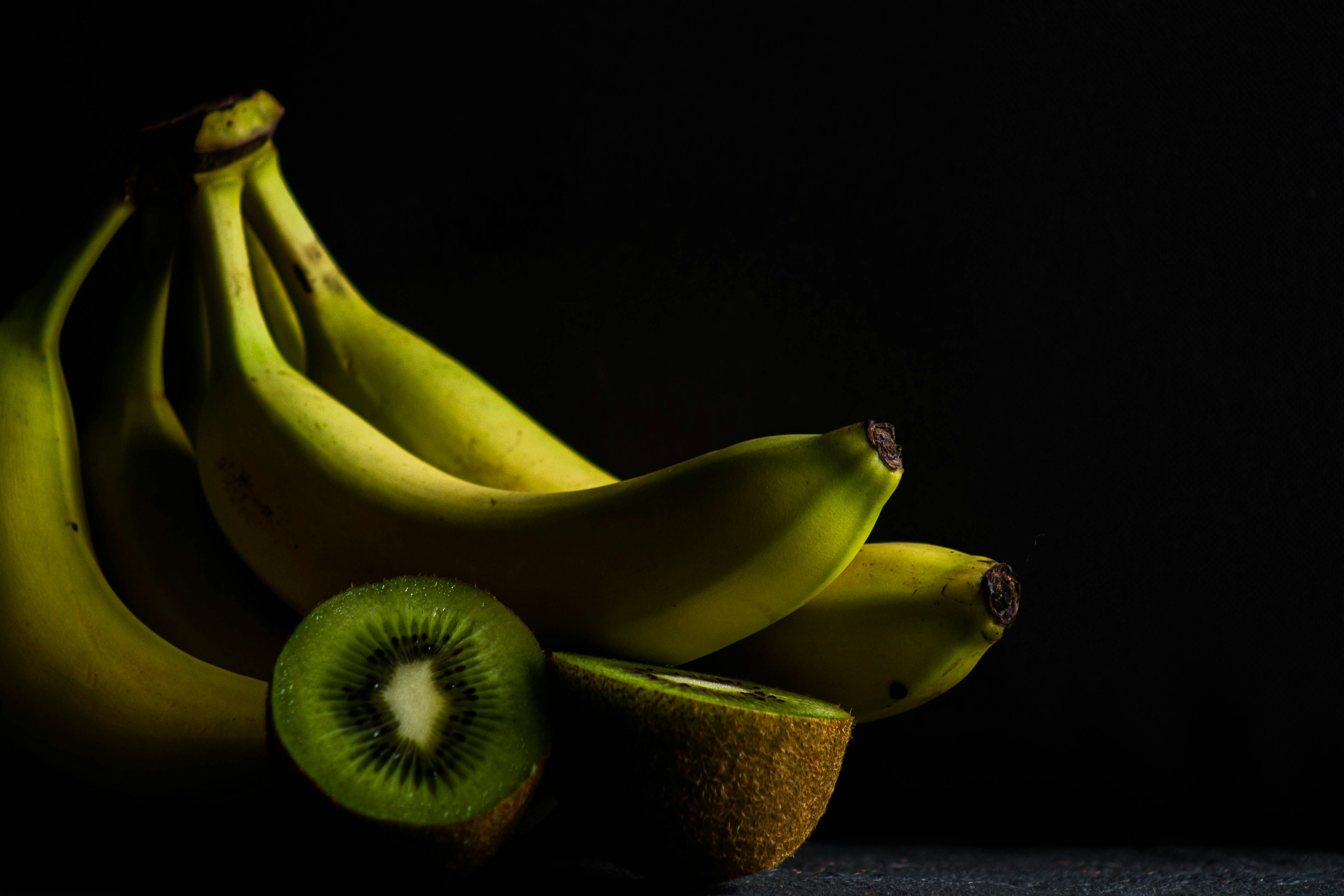 Bananas and kiwi in gentle light: a still life with dark background
