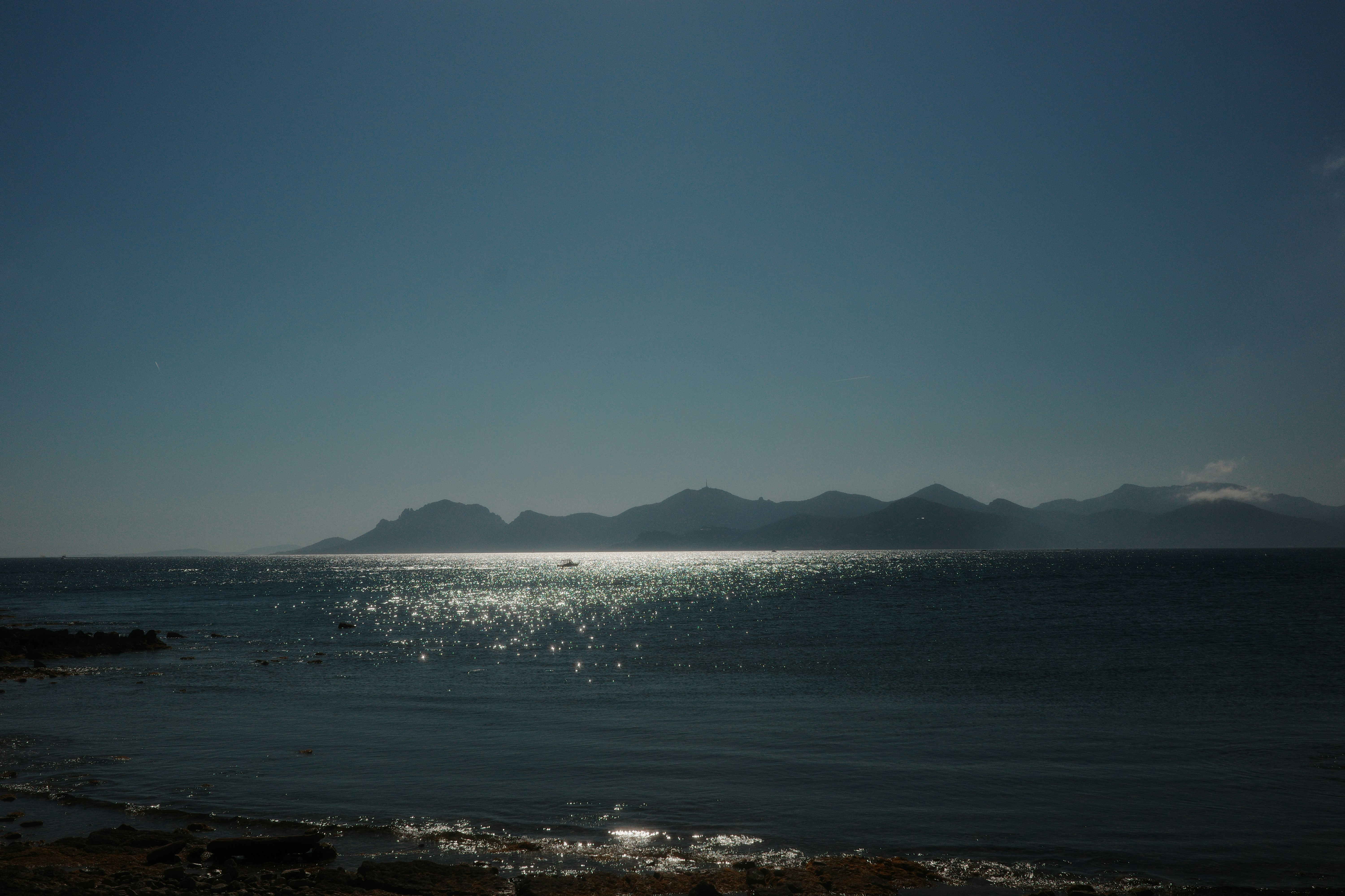 Glittering Horizon: Moonlit Seascape Over Distant Peaks