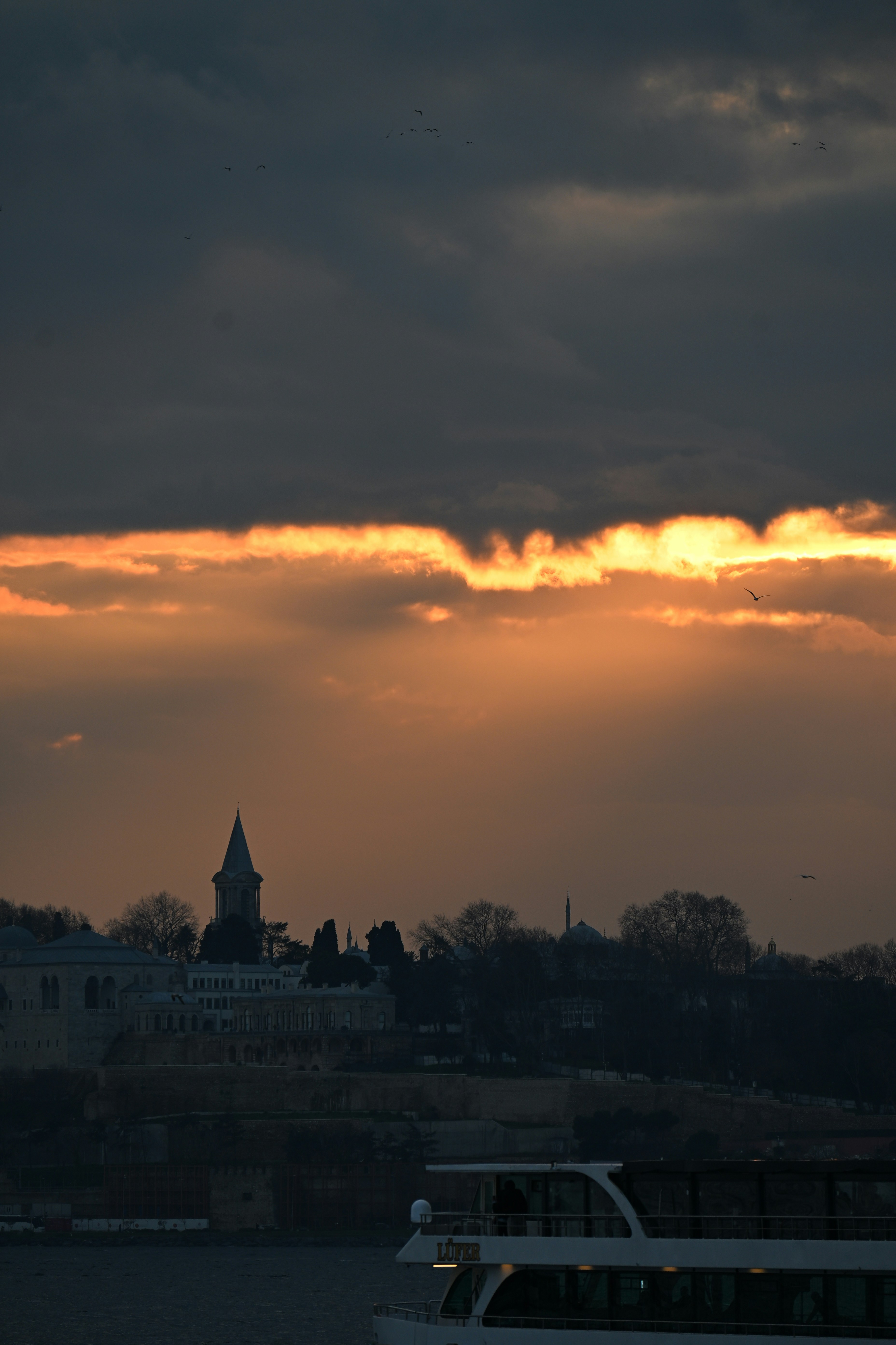 Sunset over the city silhouette with a distant river ferry
