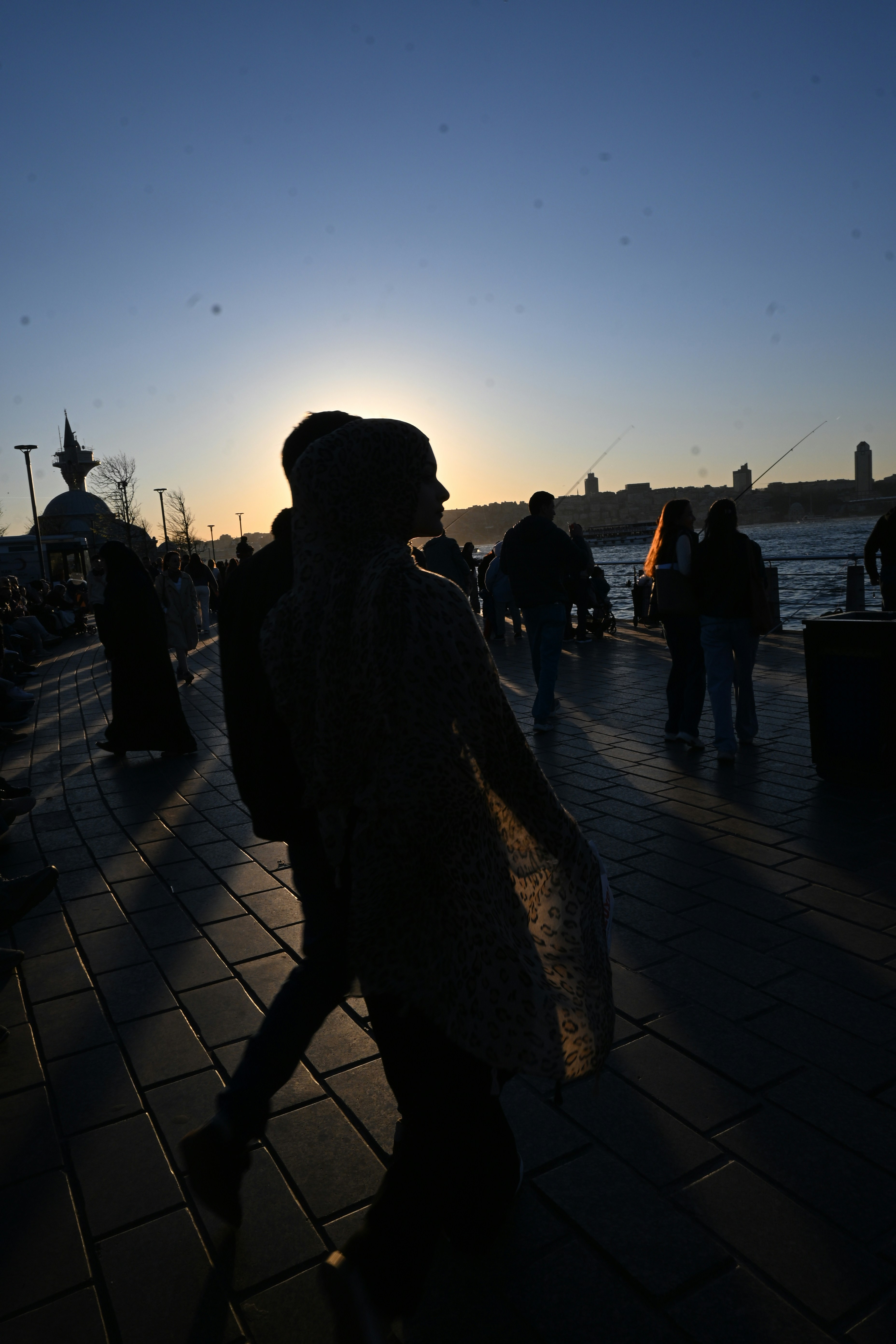 Silhouettes at Sunset by the Waterfront Promenade