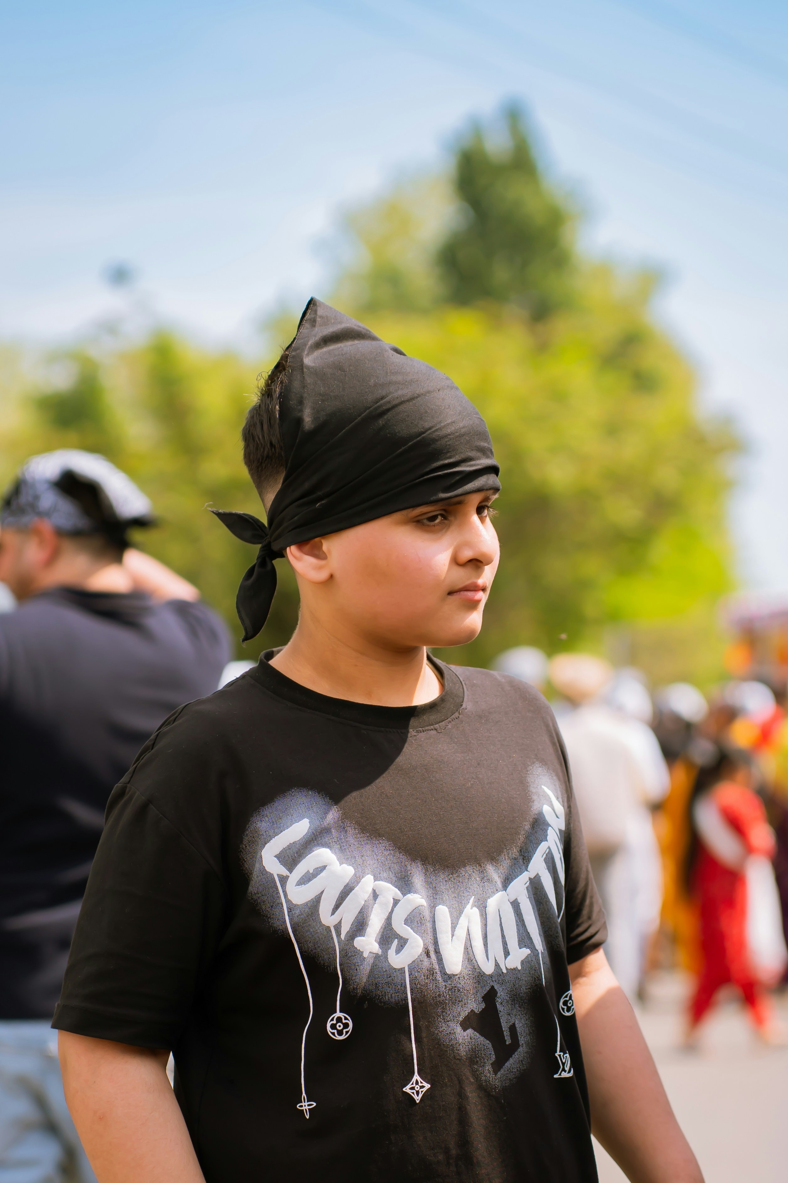 Bandana and Black Tee: Focused Portrait Amid a Vibrant Crowd