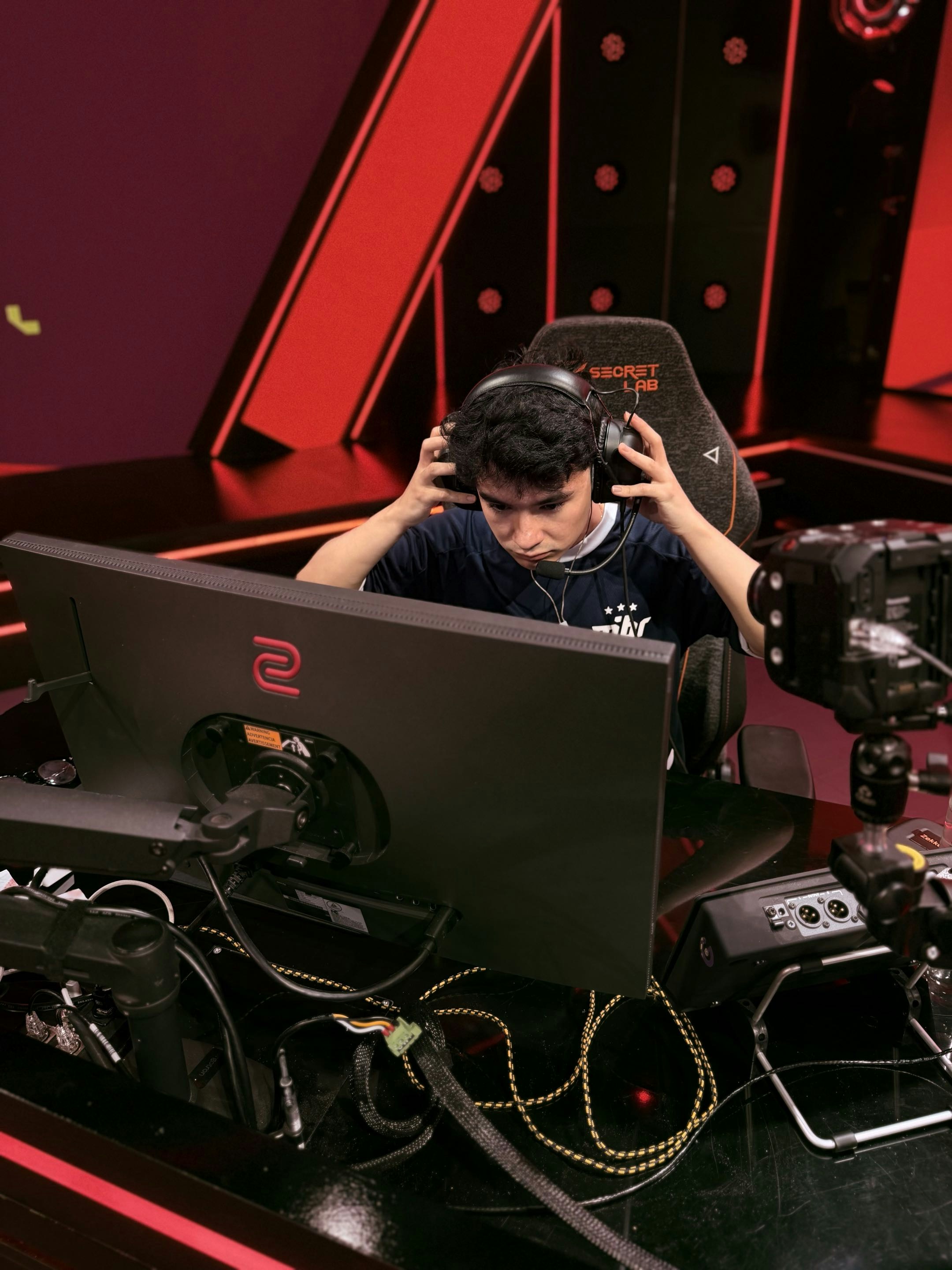 Focused gamer: headset, monitor, and rig in a red‑accented streaming setup