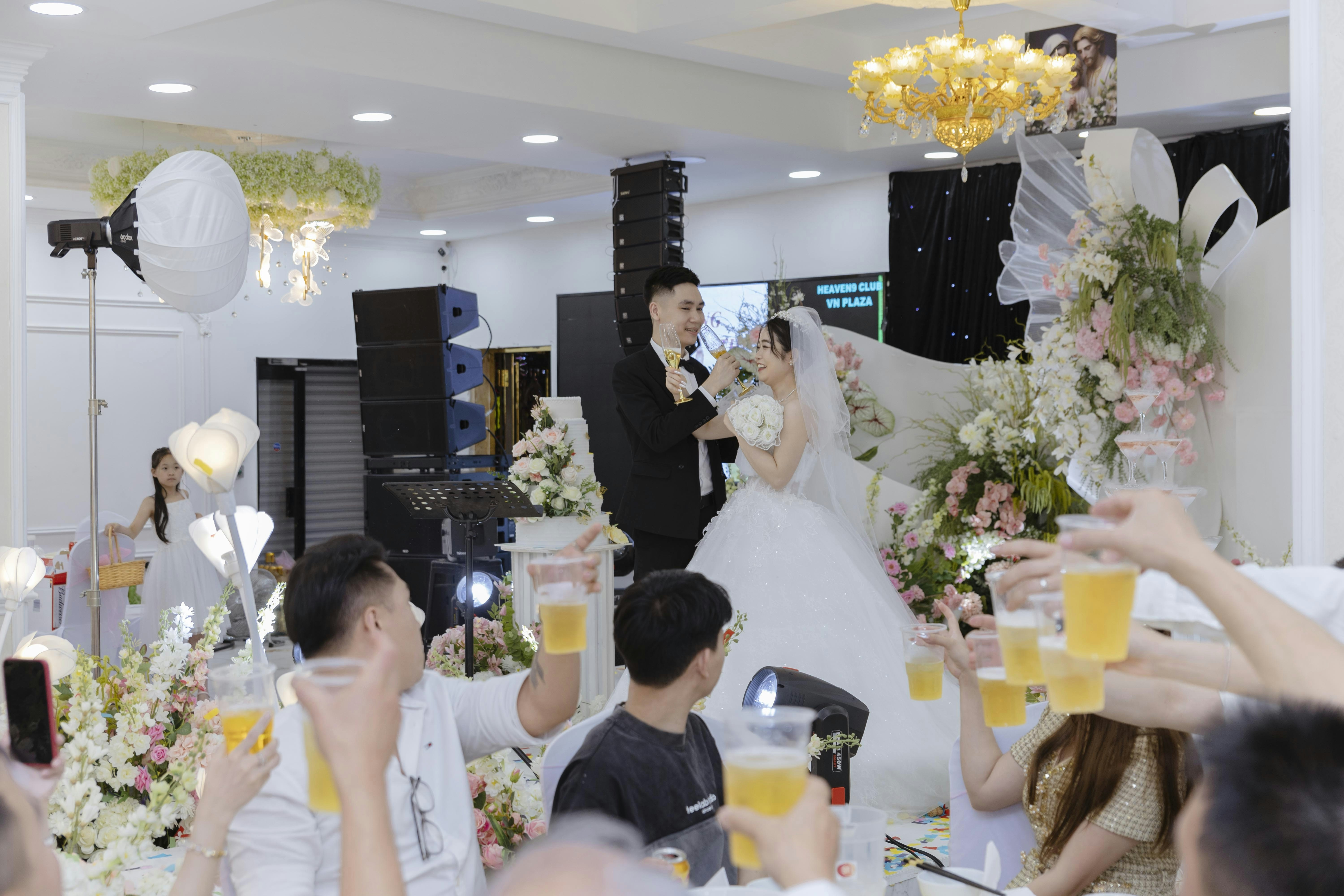 Bride and groom's first dance under floral chandelier as guests toast