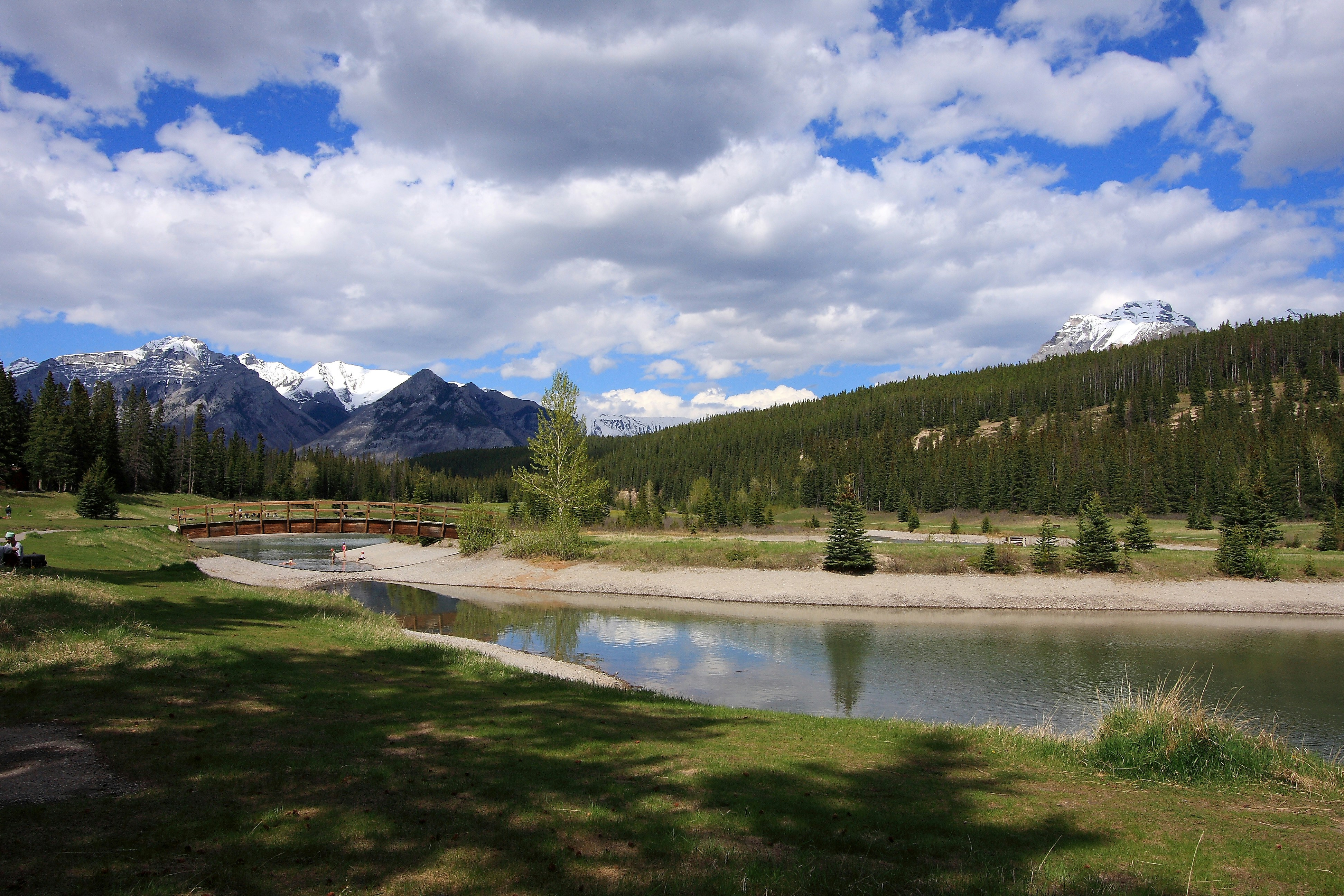 Bridge over a tranquil alpine lake under a sky of drifting clouds