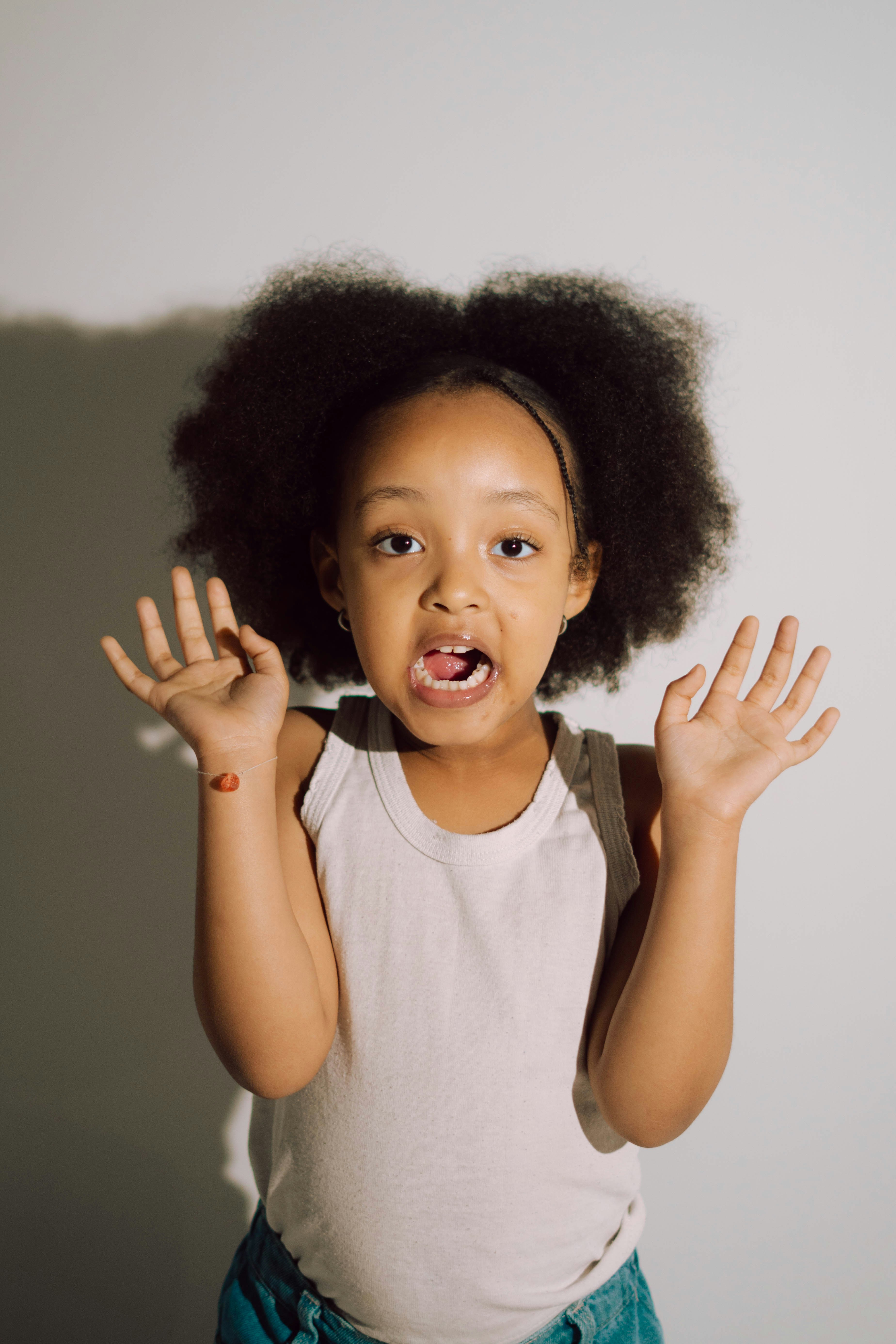 Expressive Portrait of a Curious Child with Hands Raised