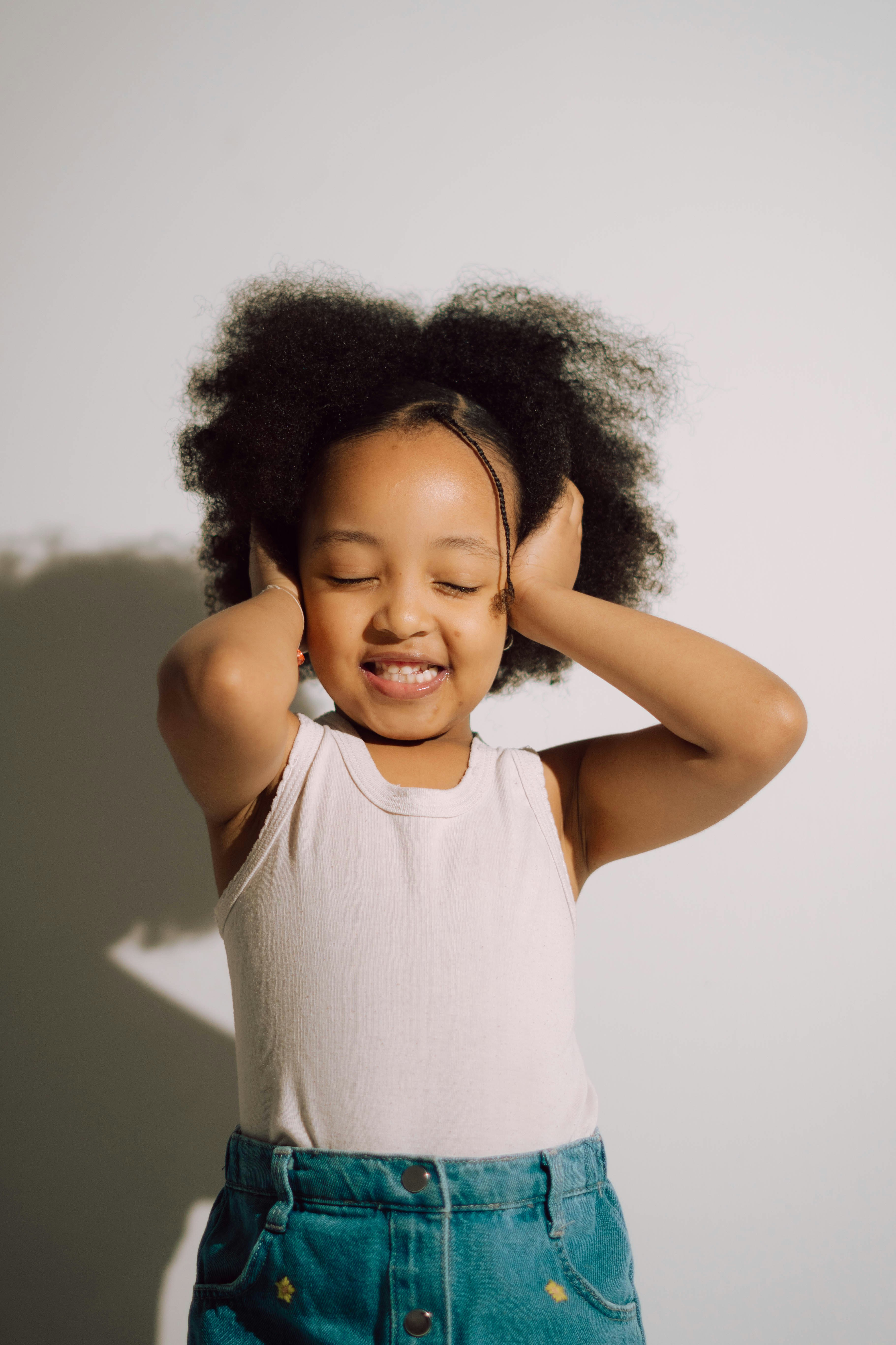 Joyful Moment: A Little Girl in a White Tank Top with Puffy Afro Hair
