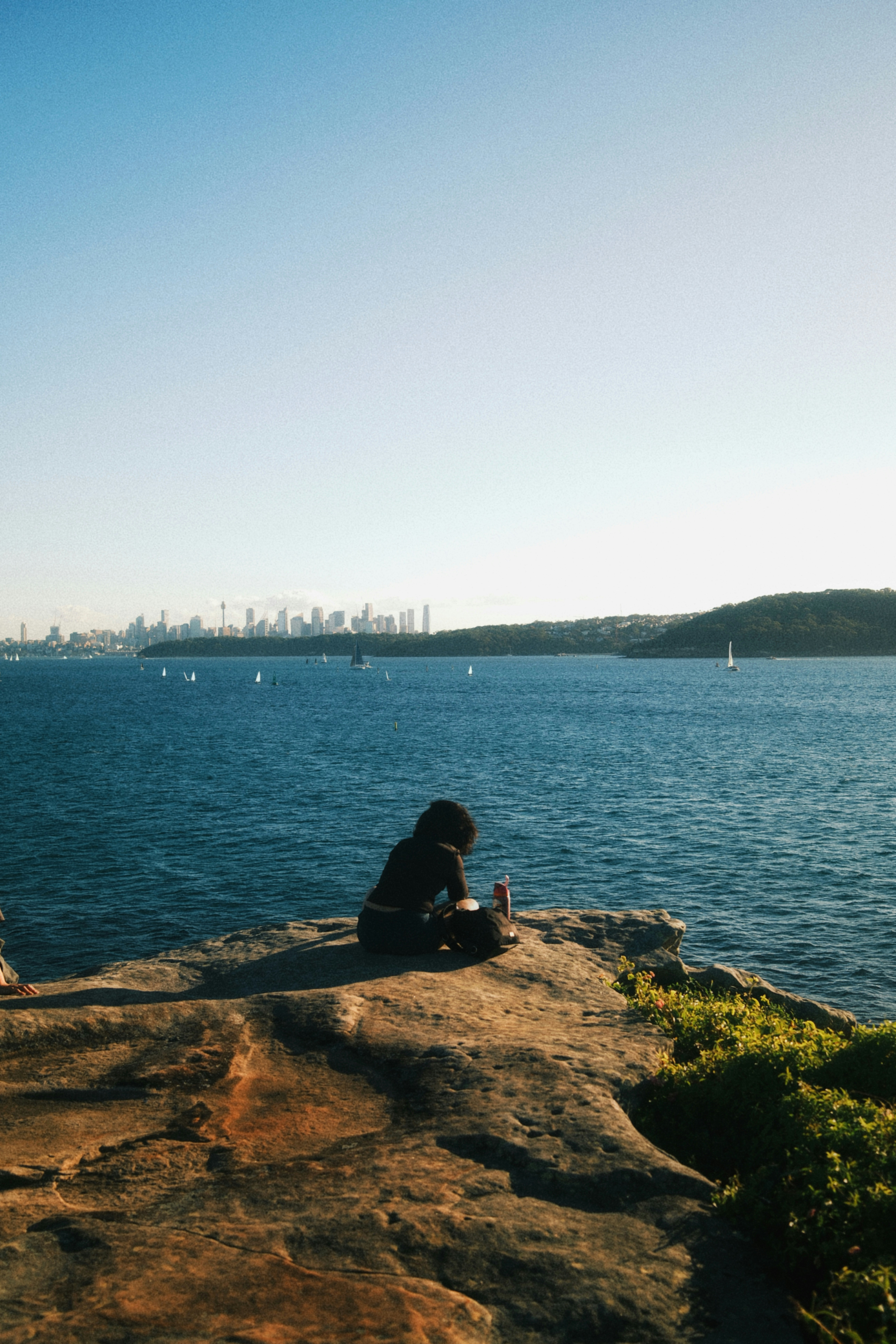 Solitary Moment on the Cliff: A Distant City by the Sea