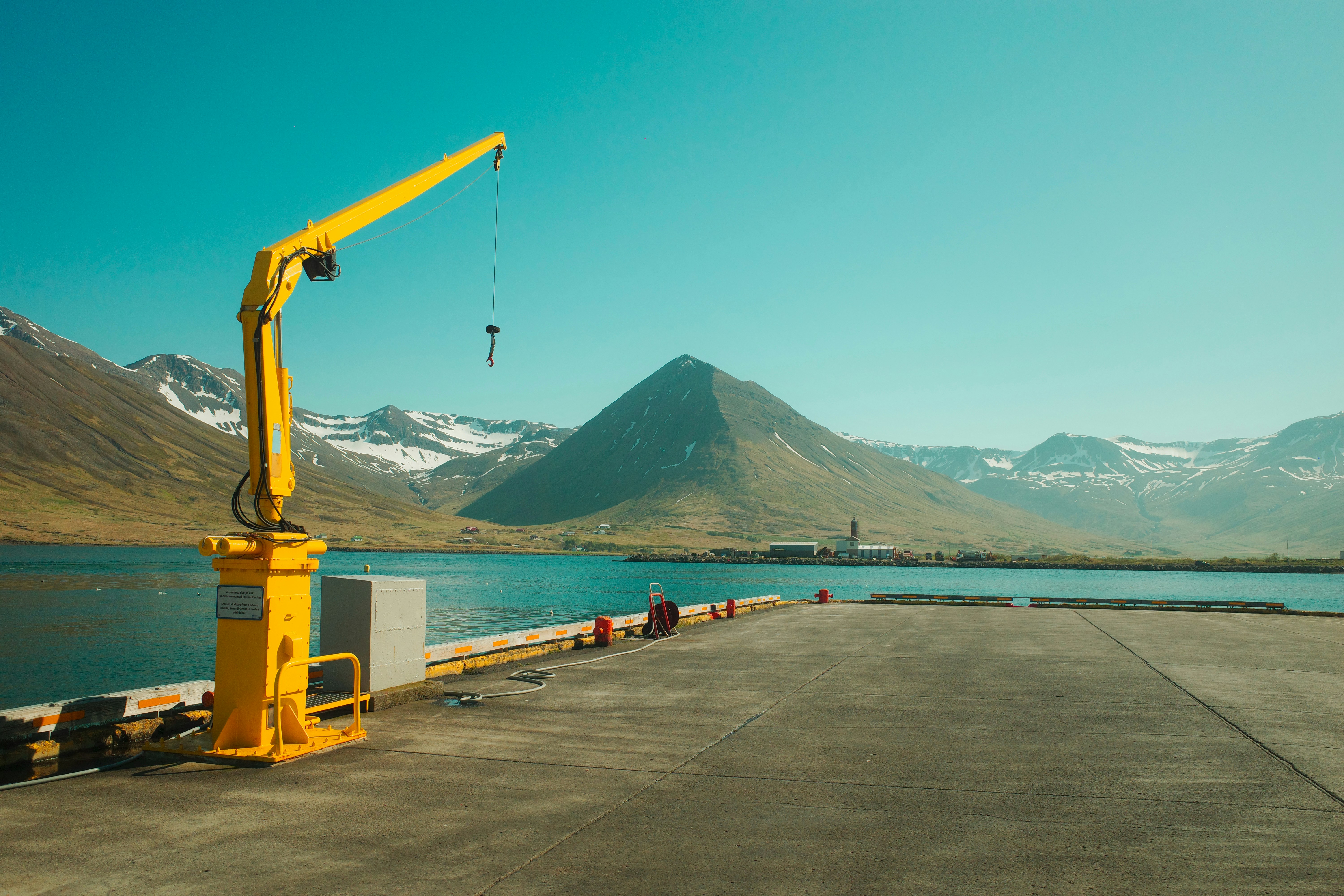Yellow harbor crane at the edge of a quiet alpine inlet