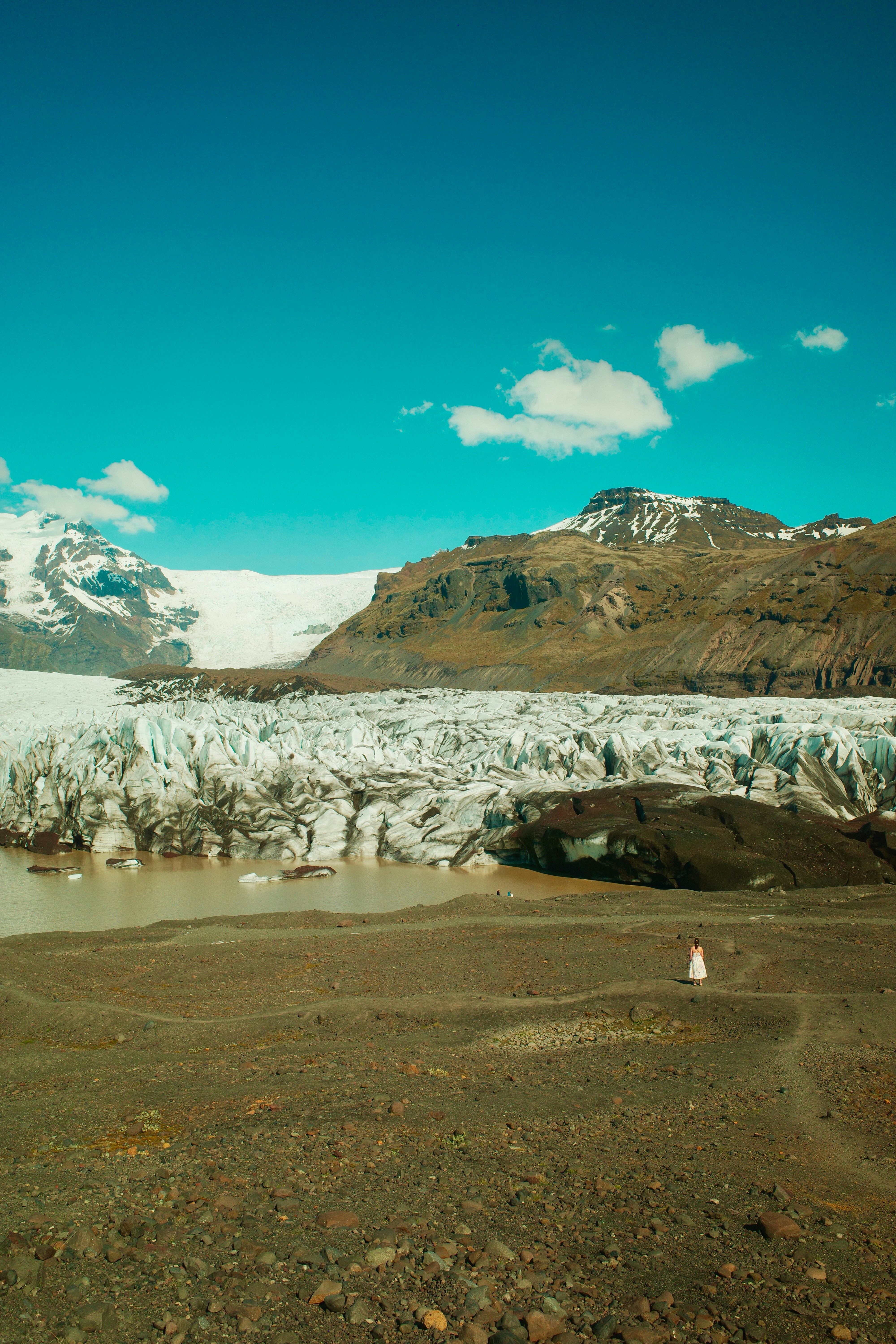 Glacial Frontier: A lone figure at the edge of a sprawling ice and rock landscape