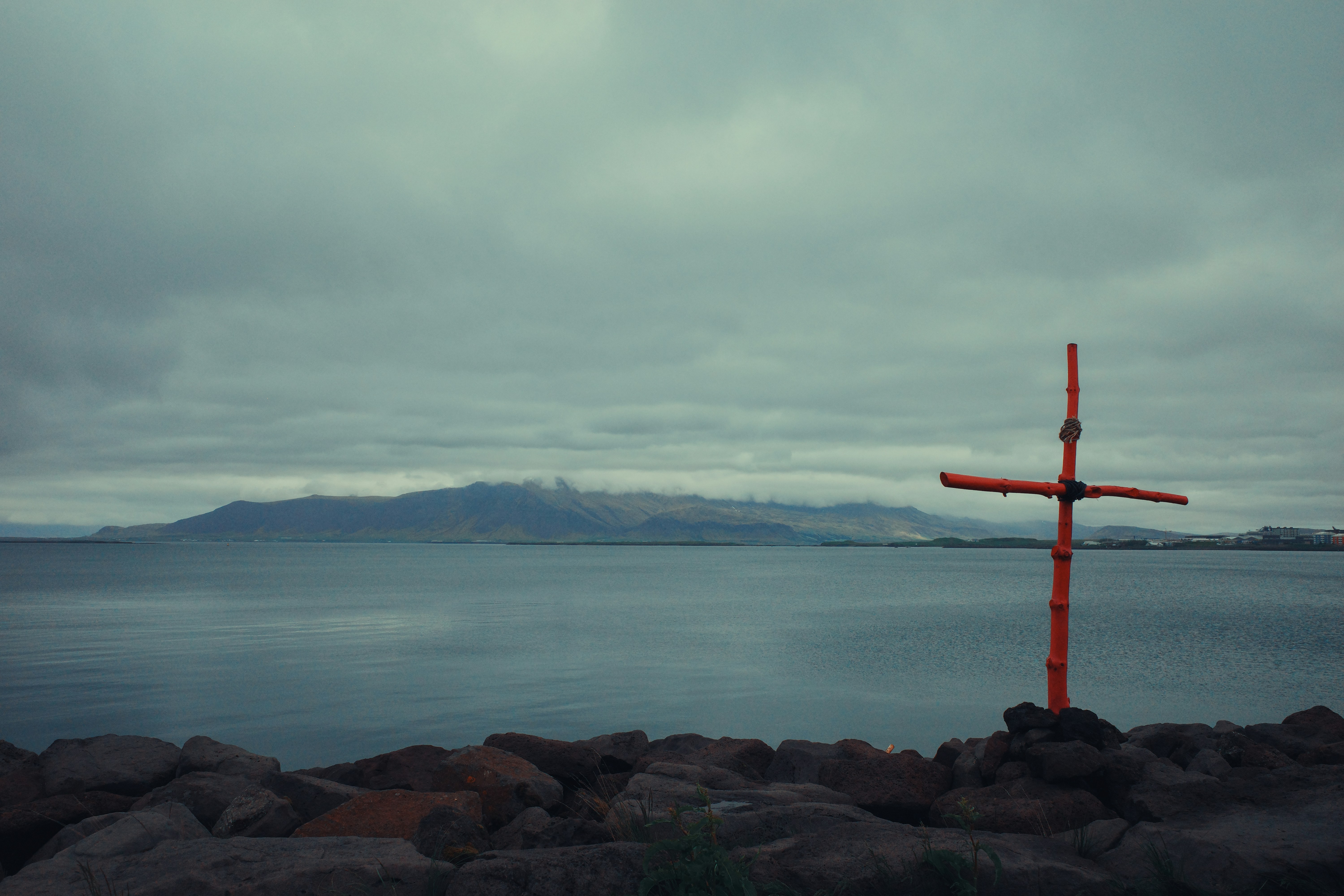Red cross by the sea: a solitary beacon against a clouded horizon