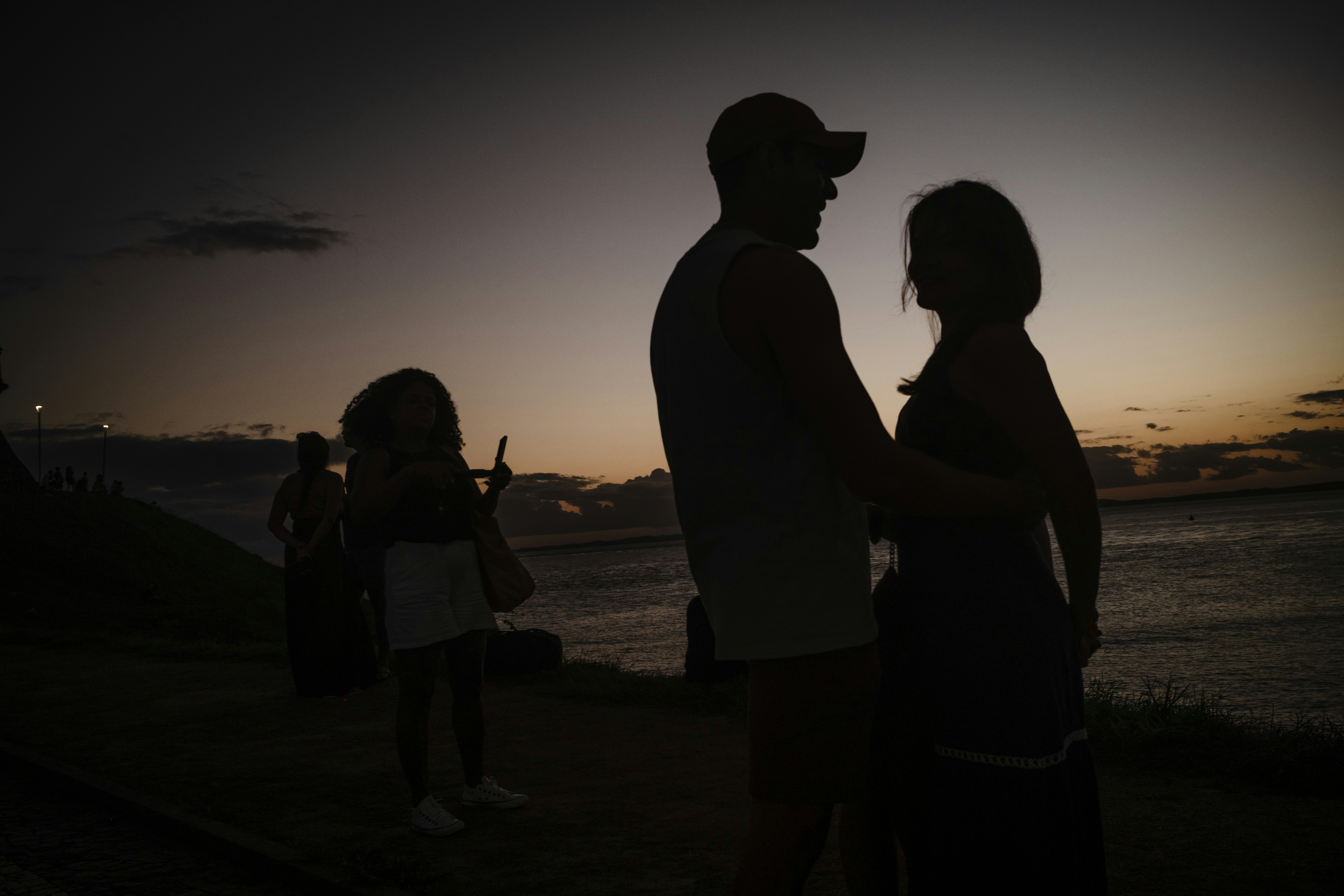 Silhouetted Couple at Dusk: Quiet Connection by the Water