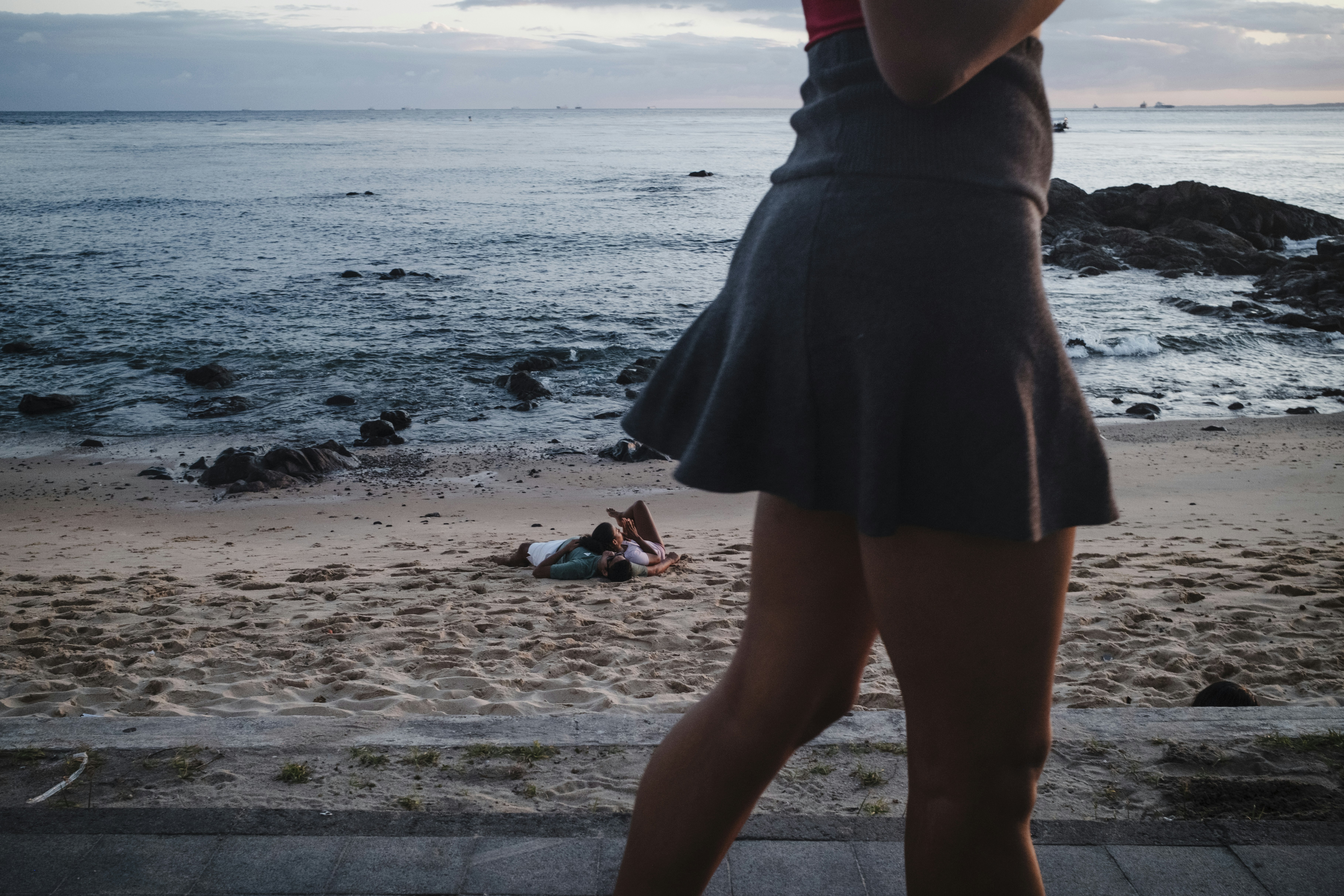 Skirted Figure at Dusk: A Quiet Beach Moment Framed by Waves