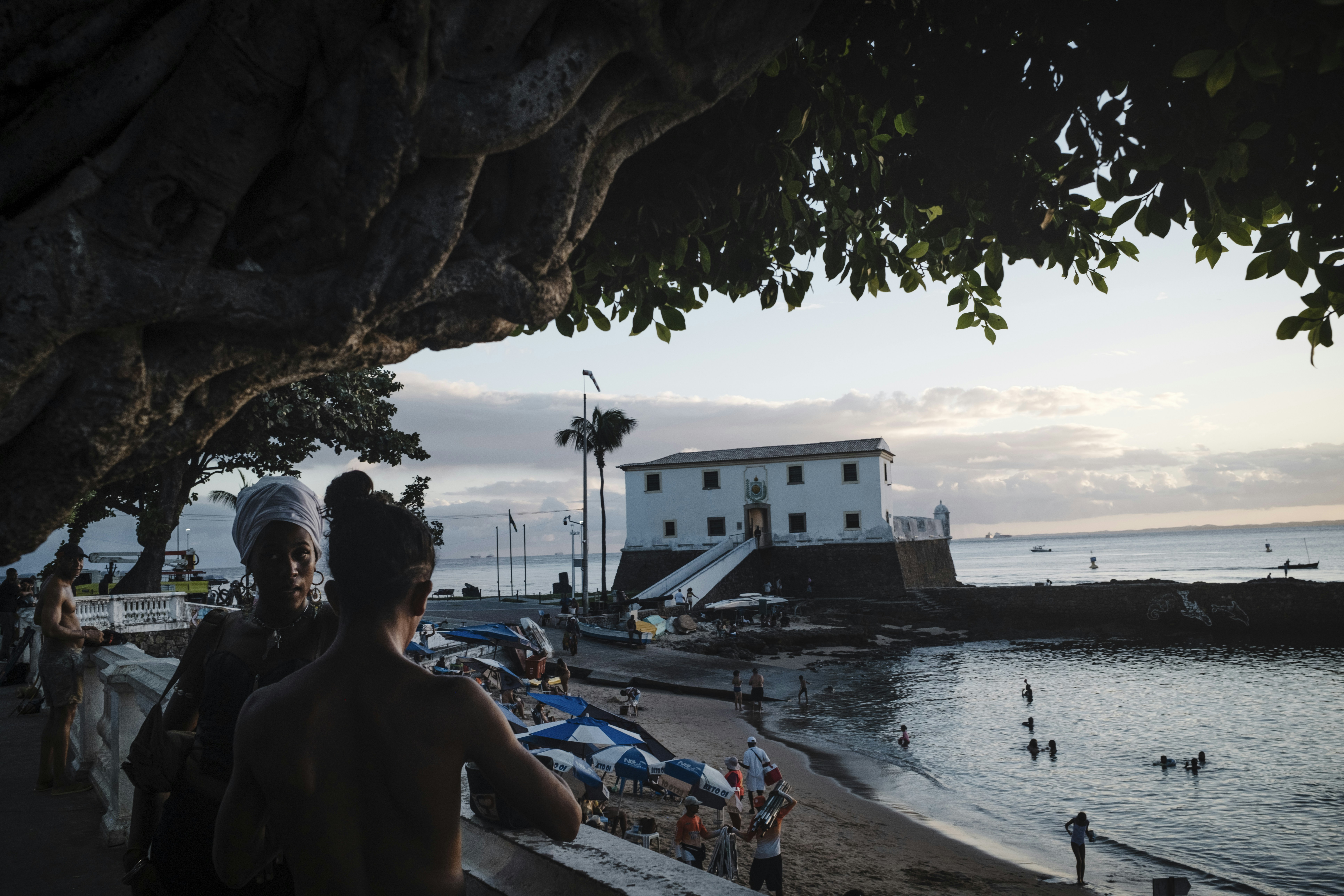 Beachside Scene under Branches: People, Boat Dock, and a Quiet House by the Sea