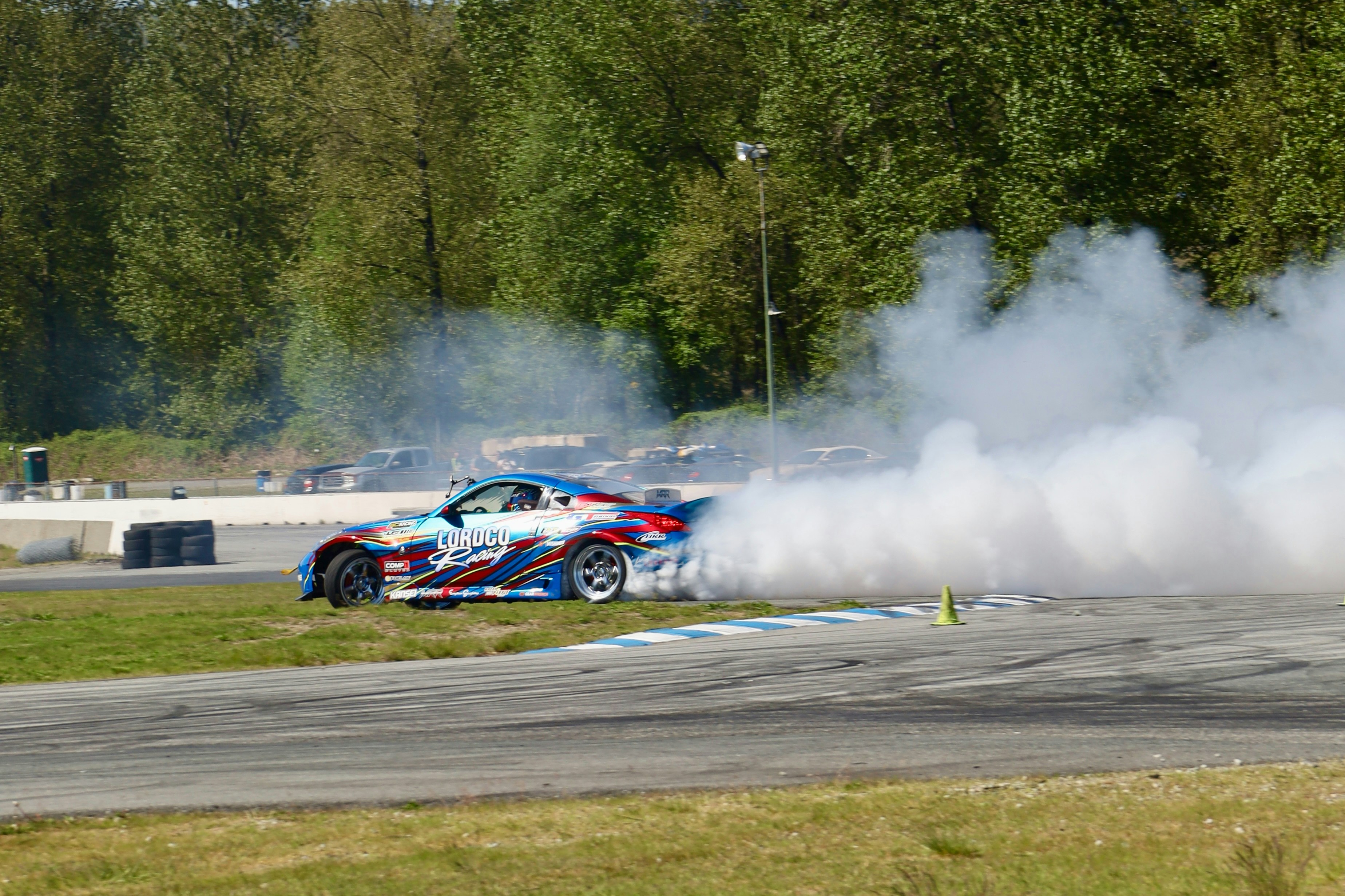 Blue-and-white drift: a sprint car powers through smoke on a track