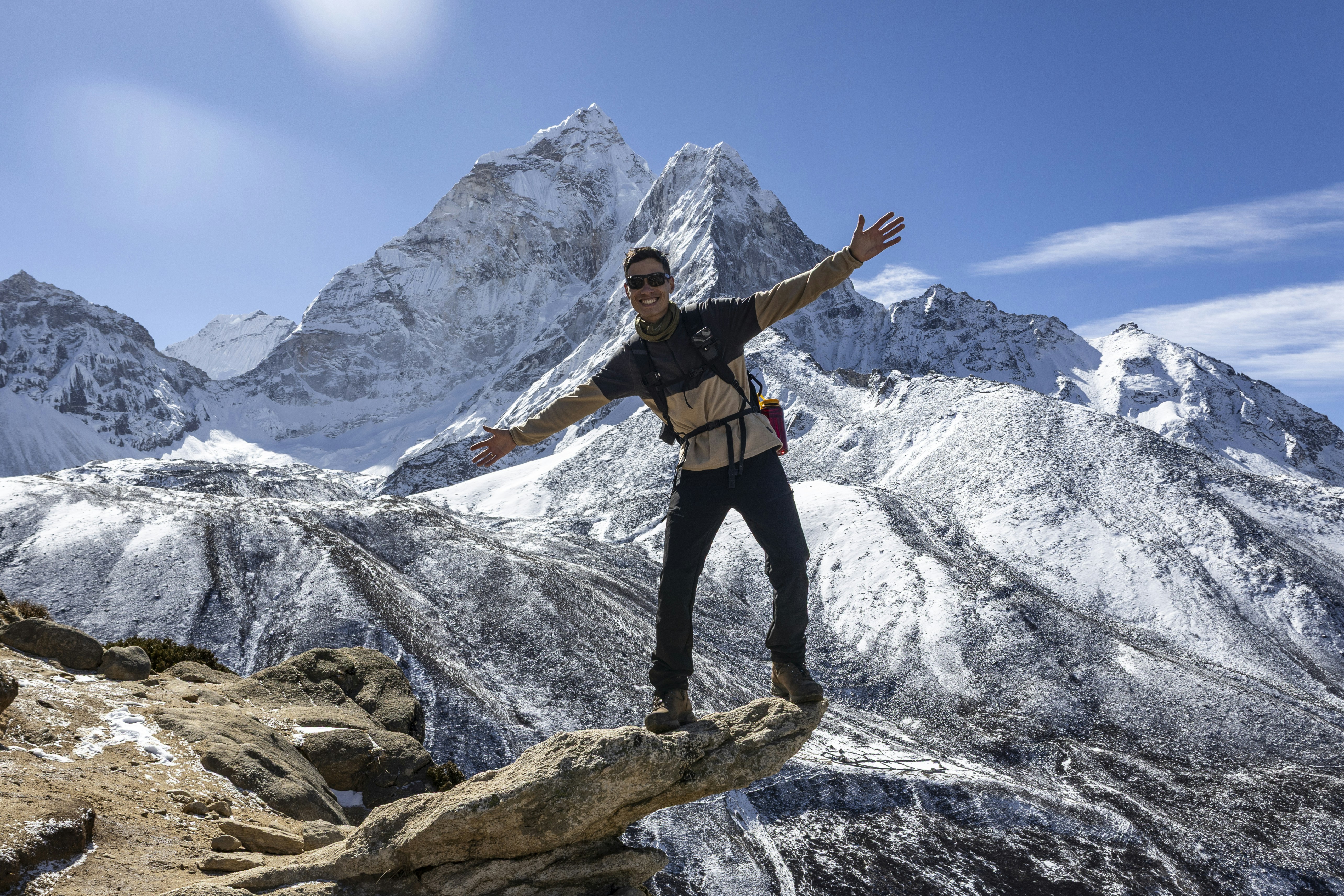 Balancing on the Edge: climber on a wind-sculpted ledge beneath jagged peaks