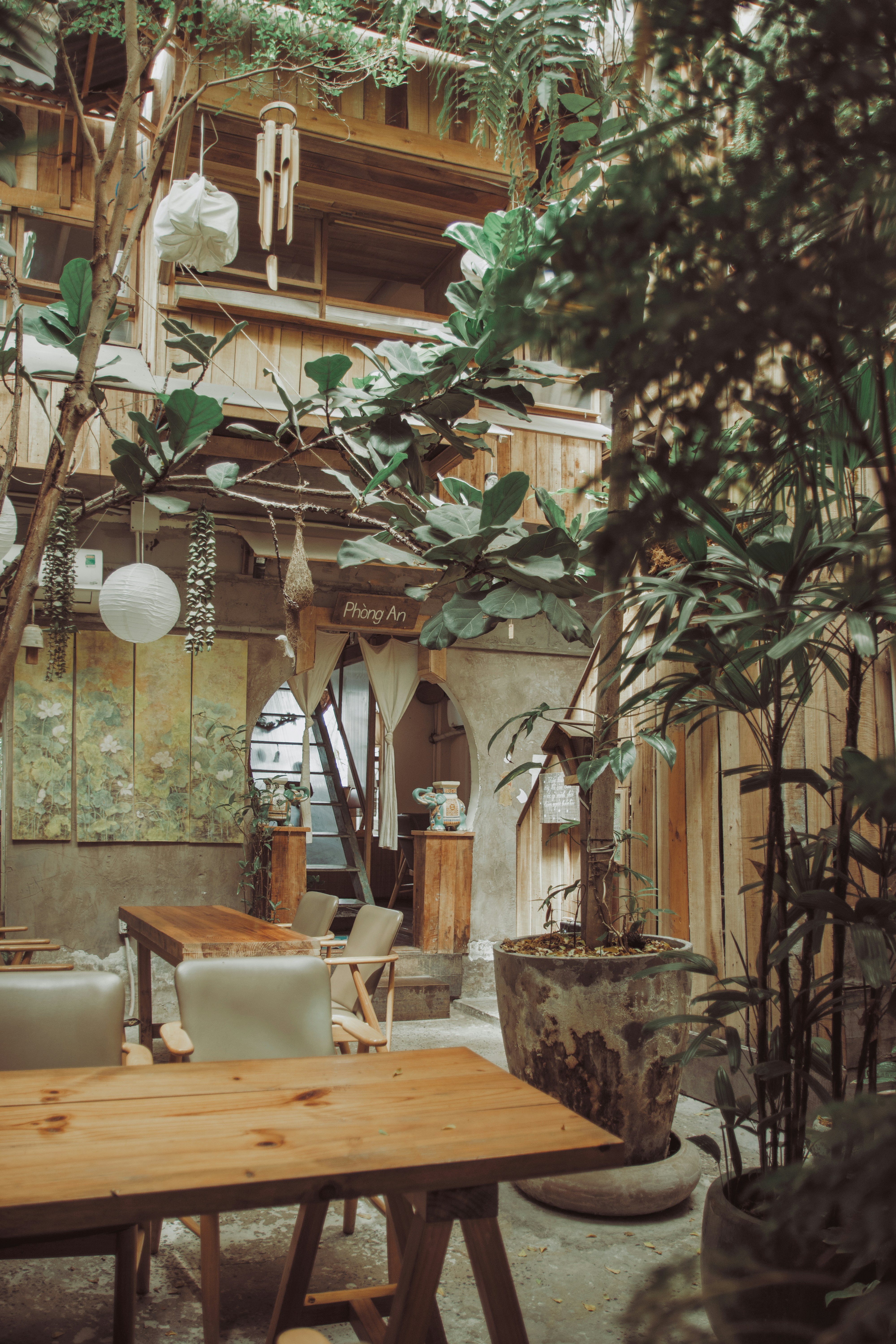 Cafe in a Verdant Atrium: Wooden Tables, Hanging Orbs, and Lush Foliage