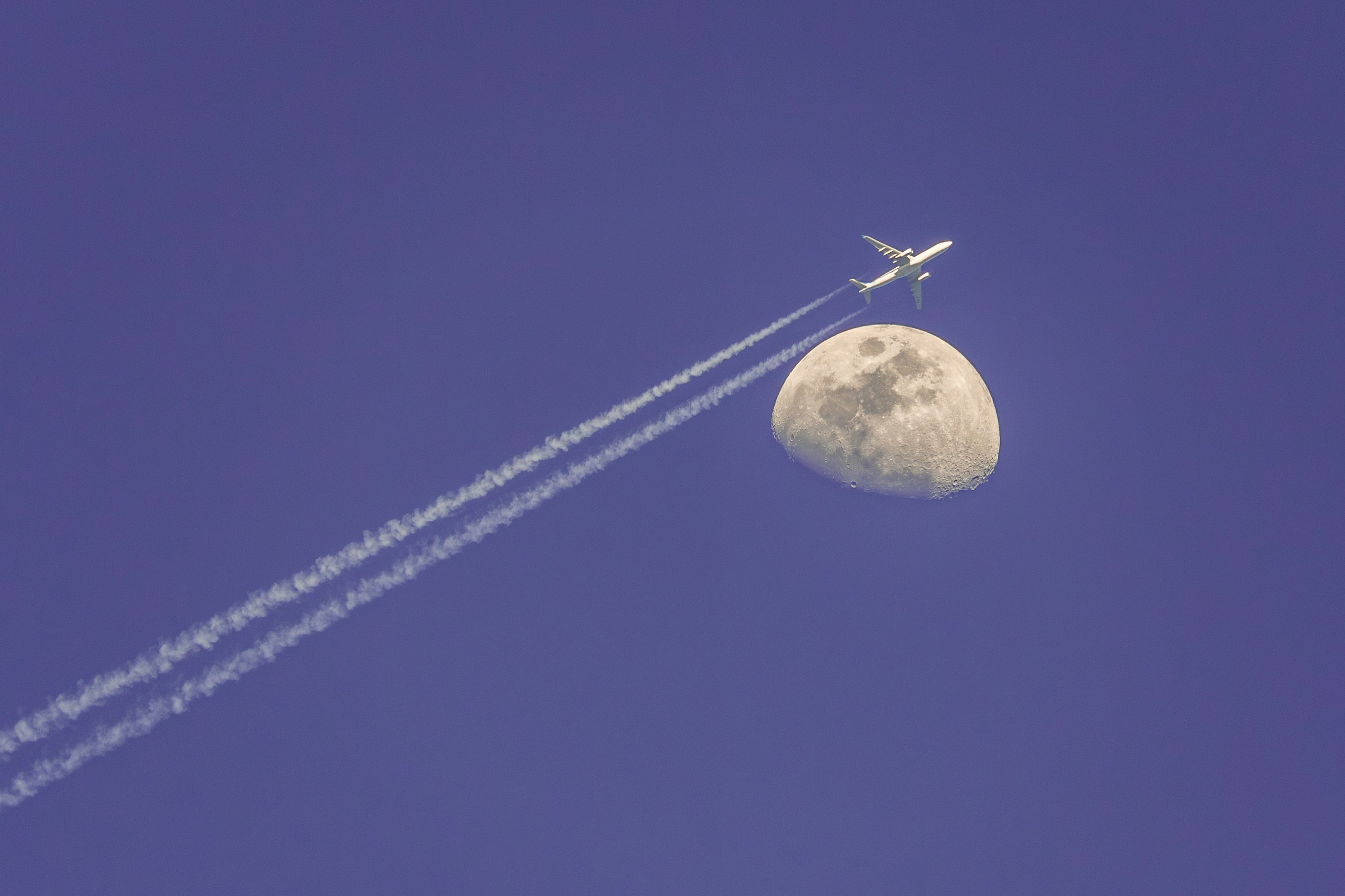 Moonlit run: jet tracing the lunar edge across a twilight sky