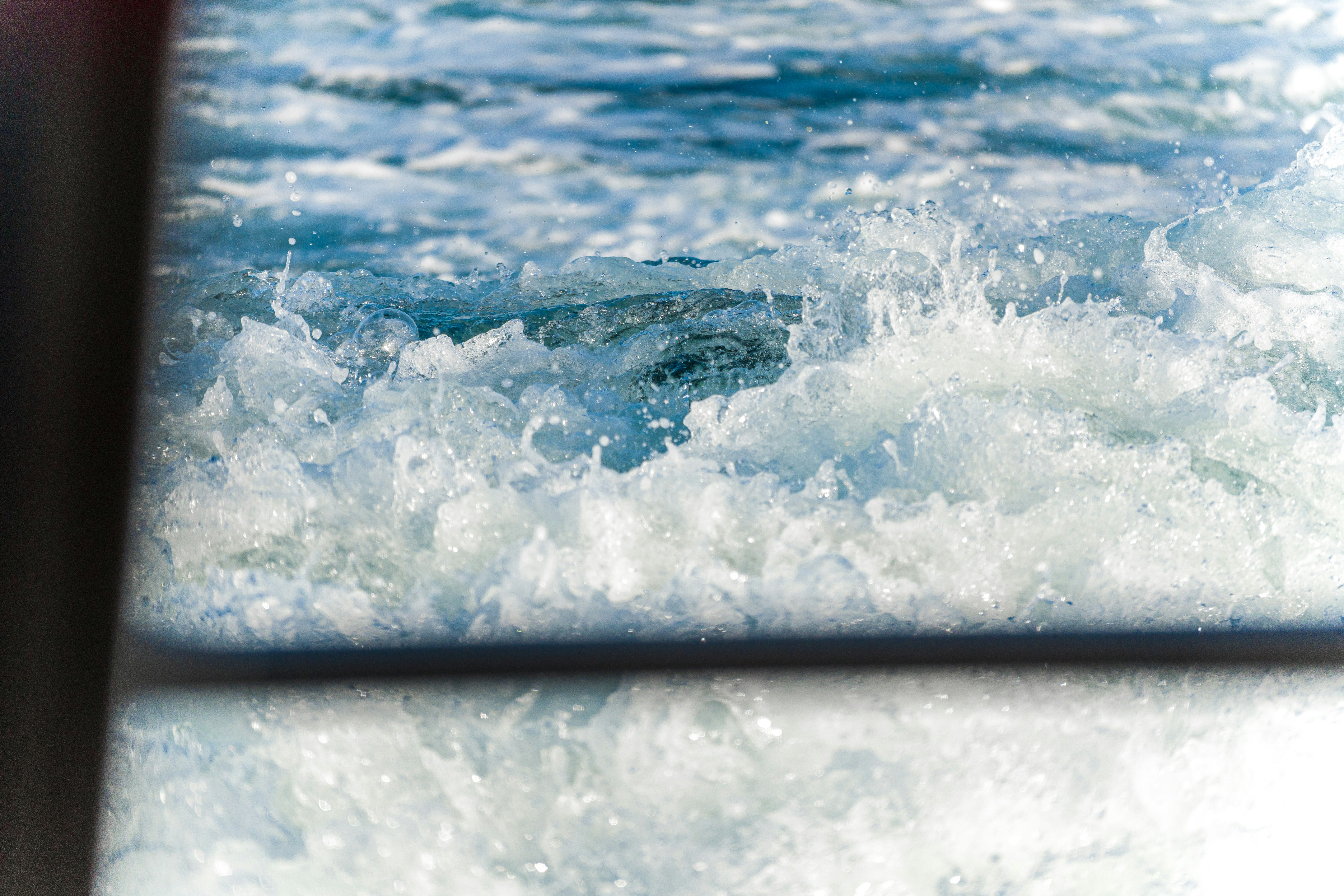 Churning blue wake through a narrow window of surf