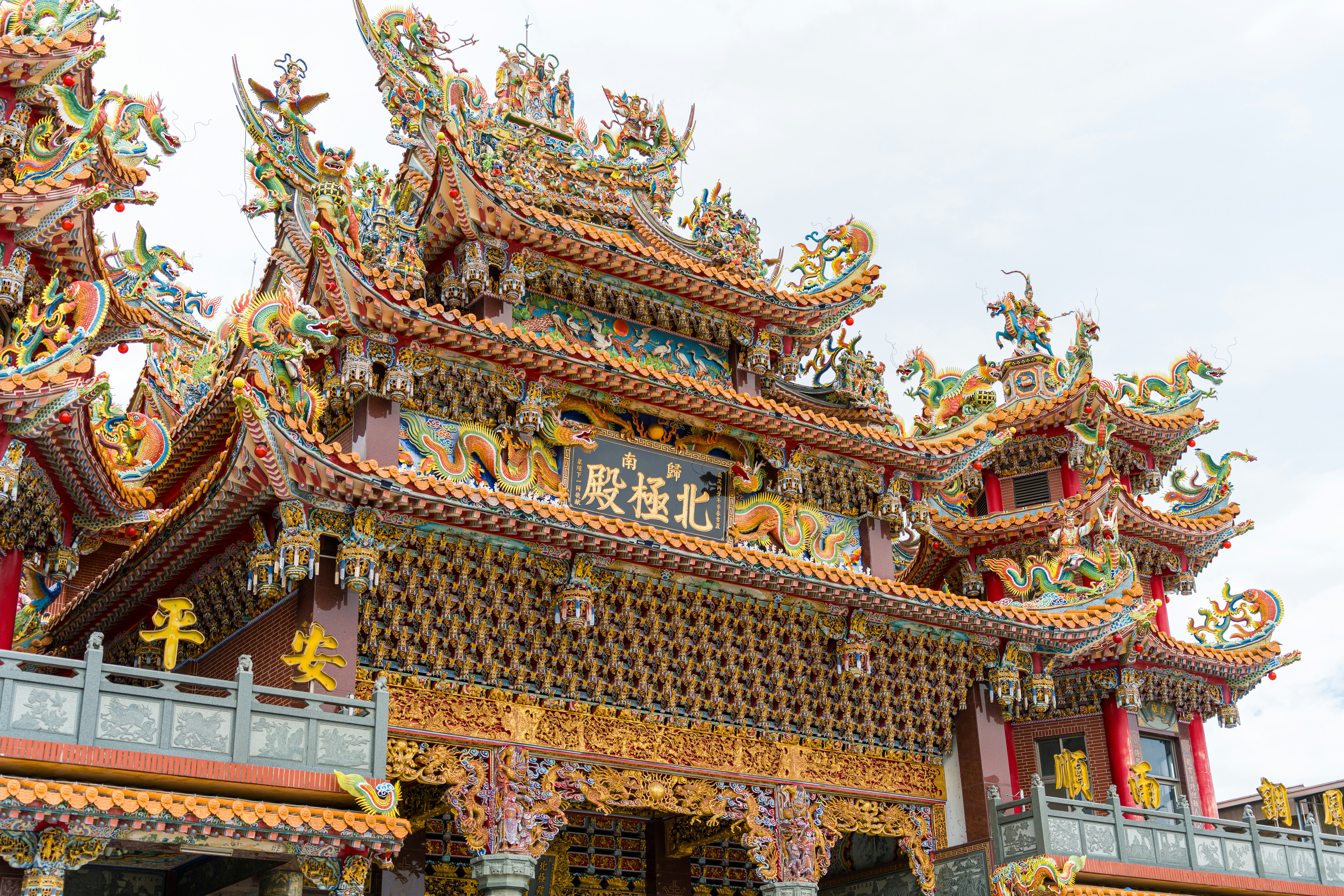 Dragon-Topped Courtyard: An Ornate Temple Facade Bursting with Colorful Carvings