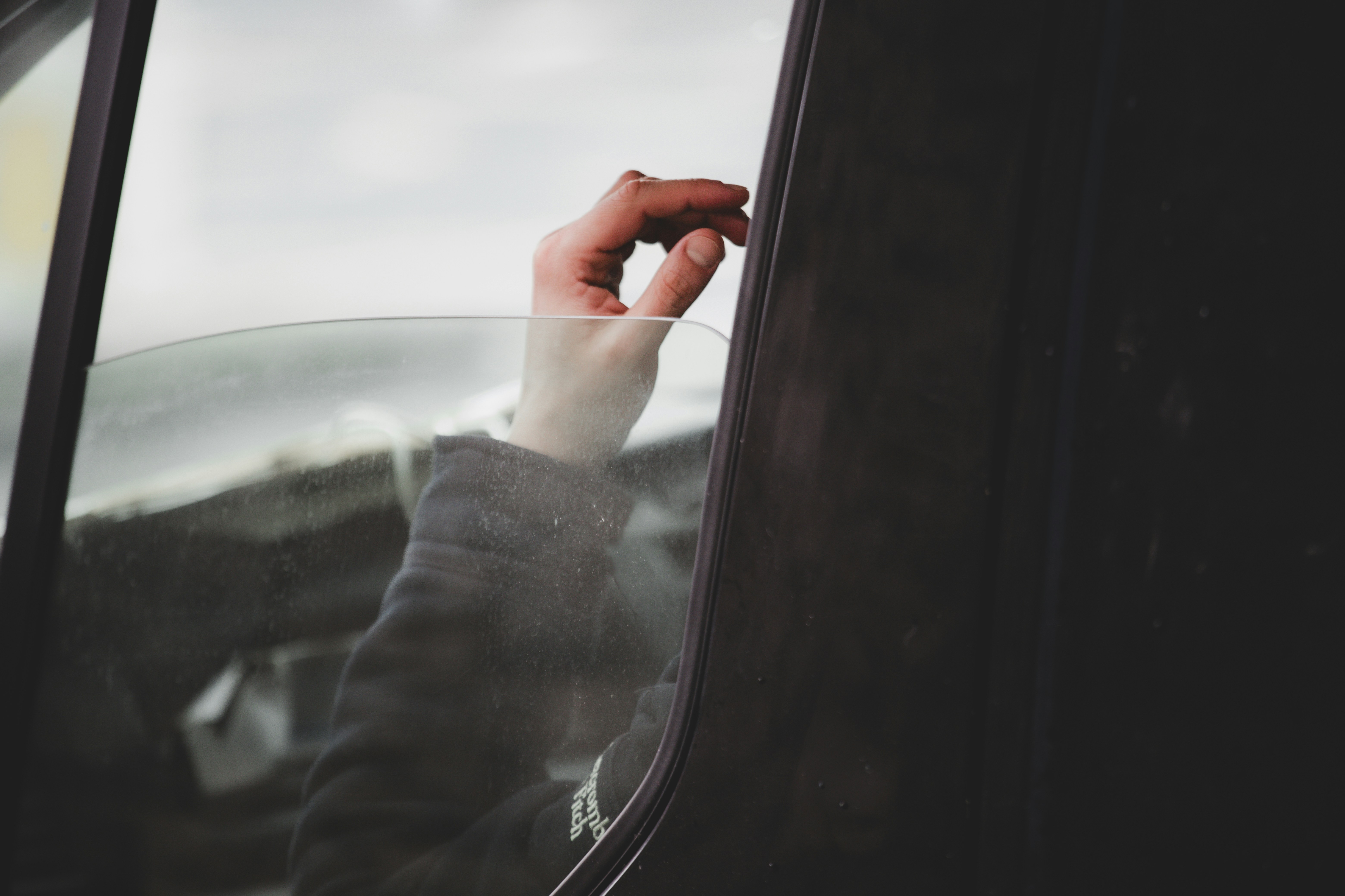 Hand in Window: Quiet Gesture Sealed Behind Dark Glass