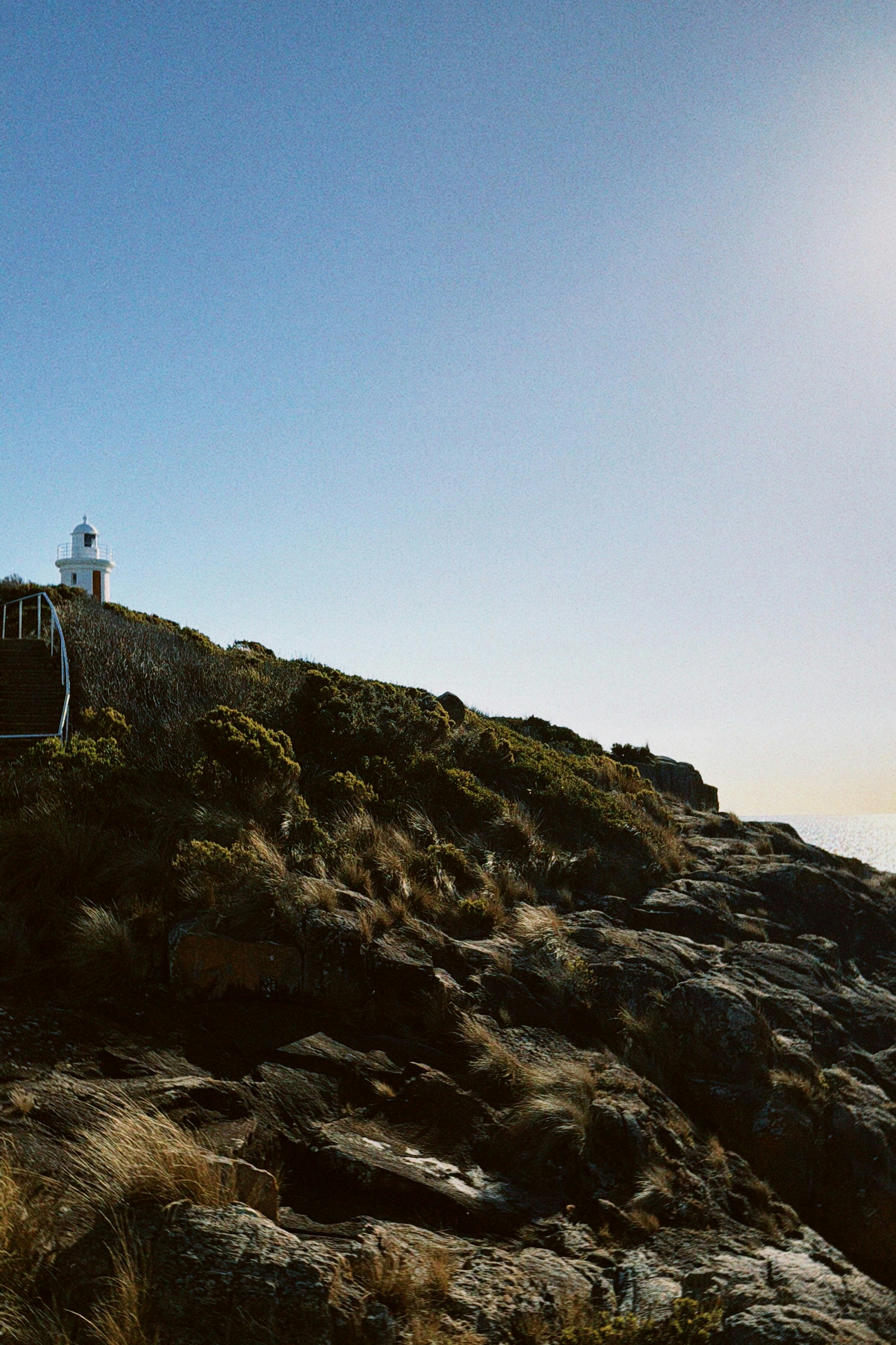 Lighthouse on the Cliff Edge under a Clear Coastal Sky