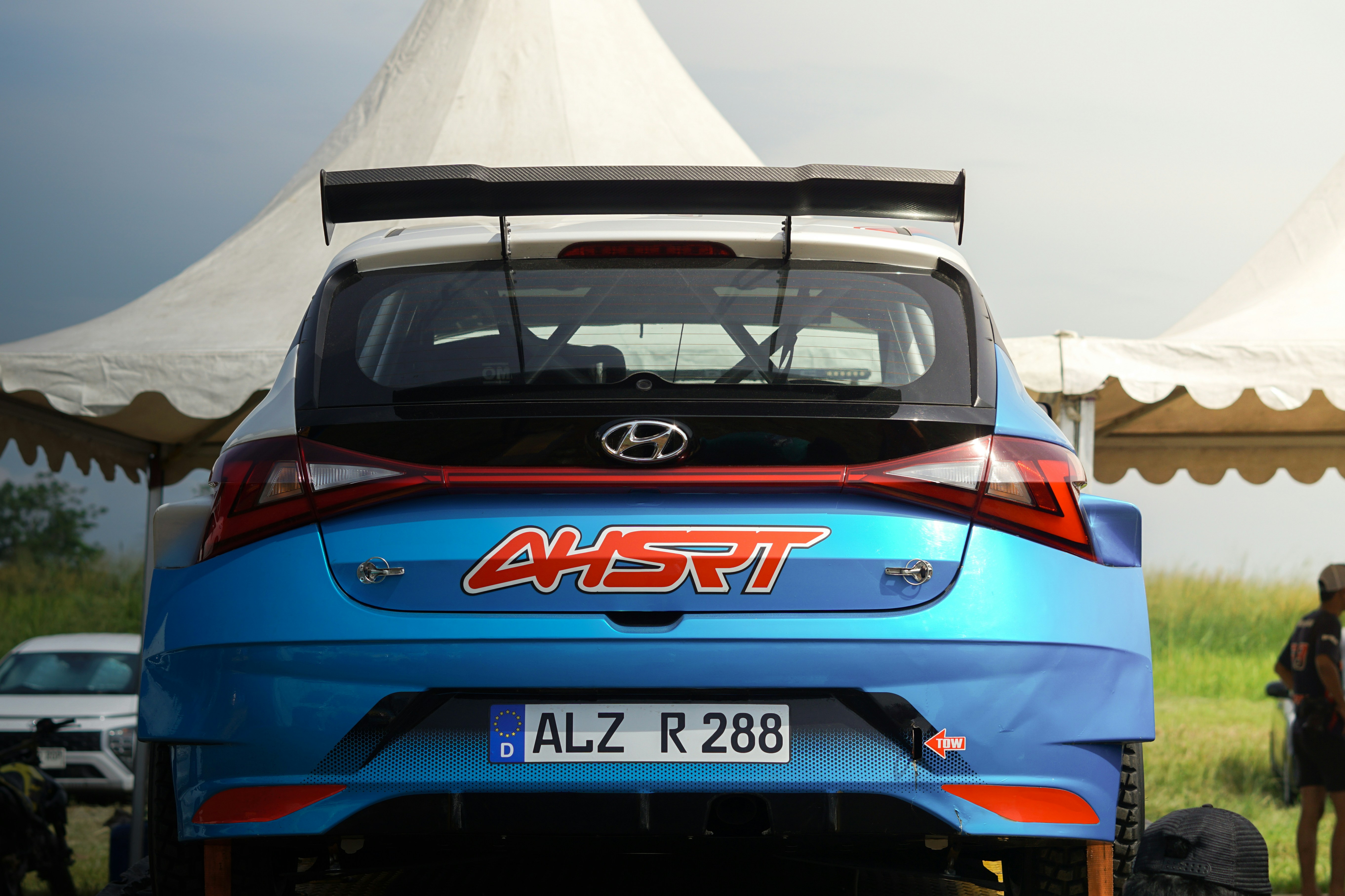 Blue Rally Behemoth: the rear of a tuned hatchback under a tent