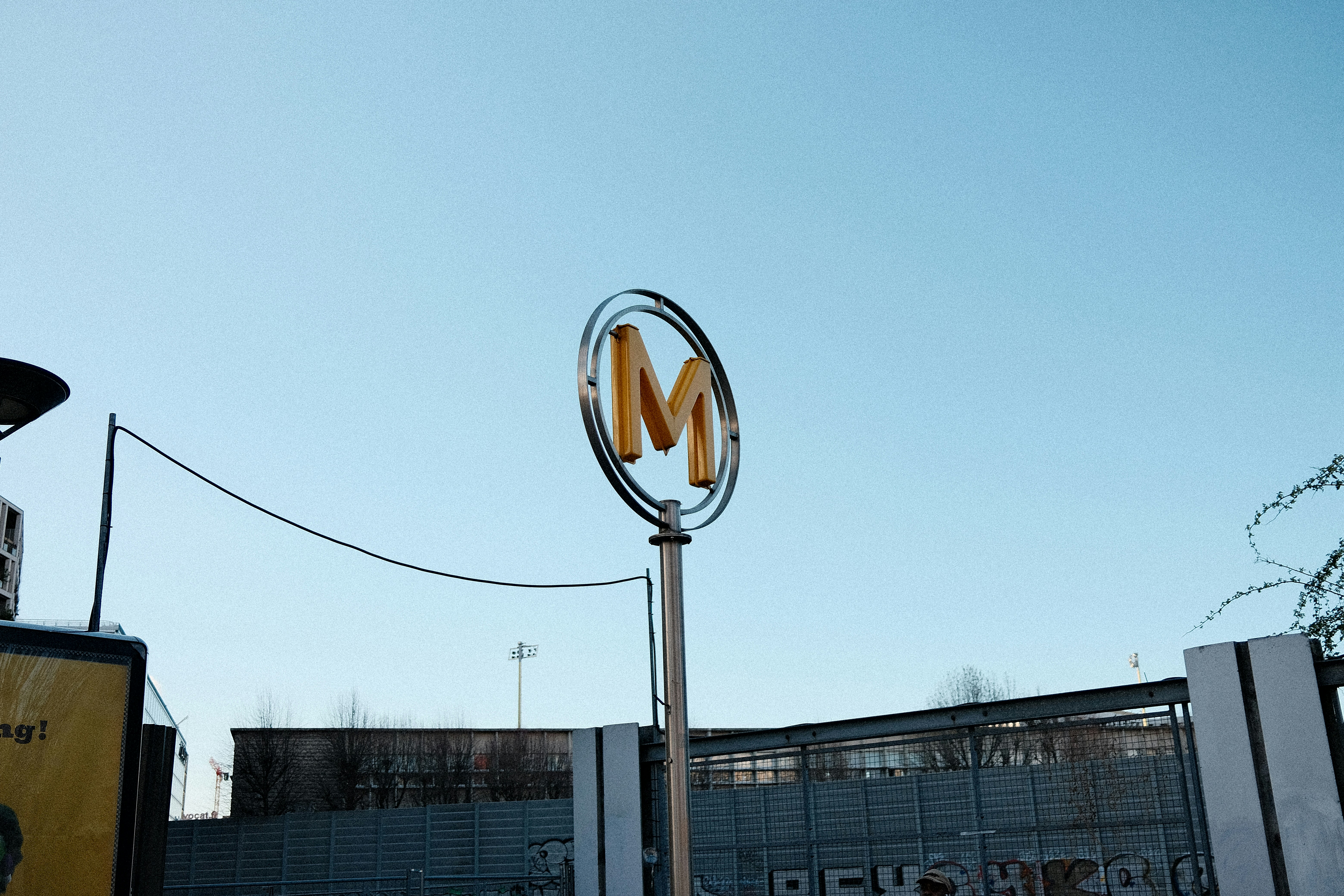 The Golden Metro Emblem Rises Above a Quiet Transit Site