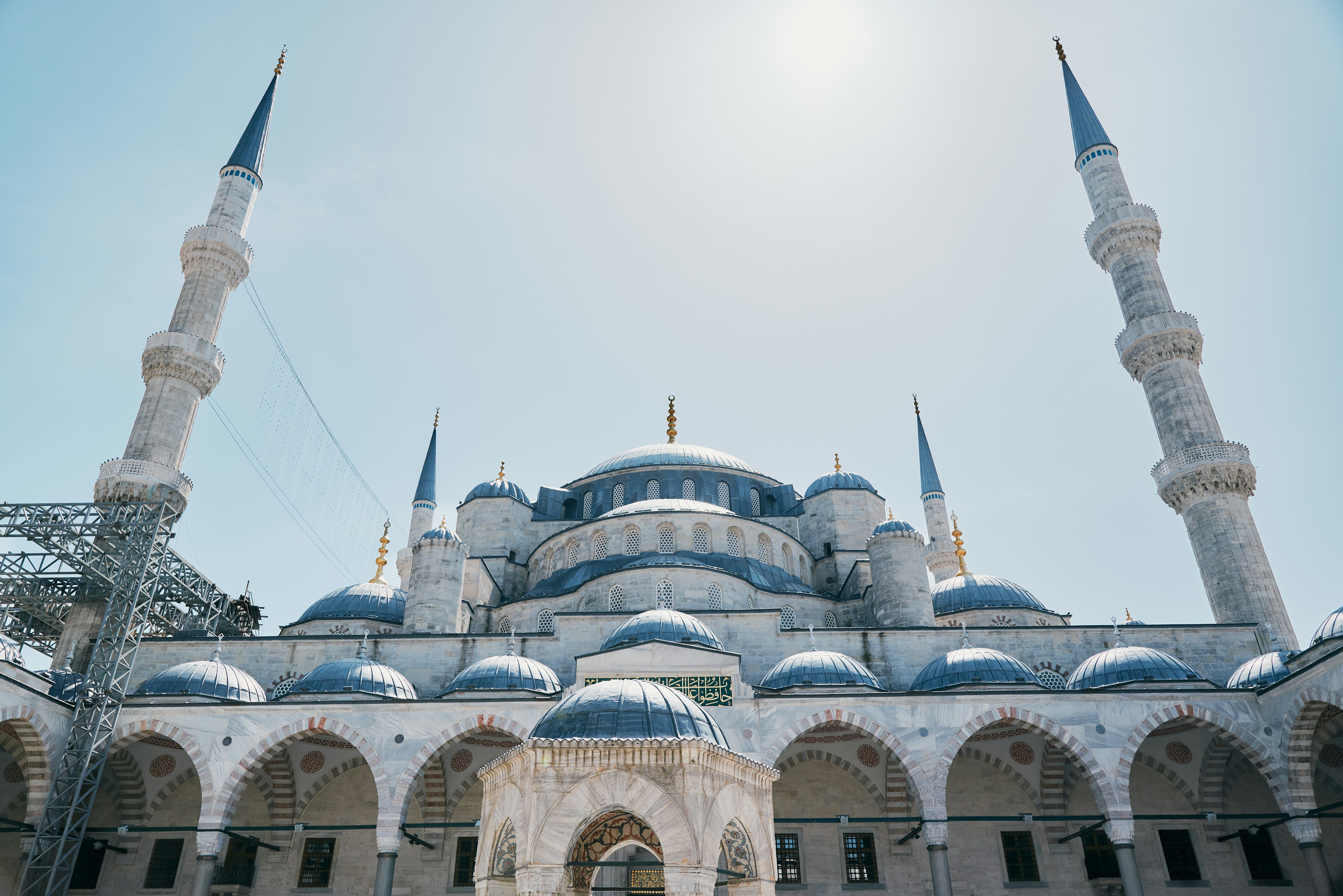 Blue Domes Under Sky: A Mosque Silhouette Against the Sun