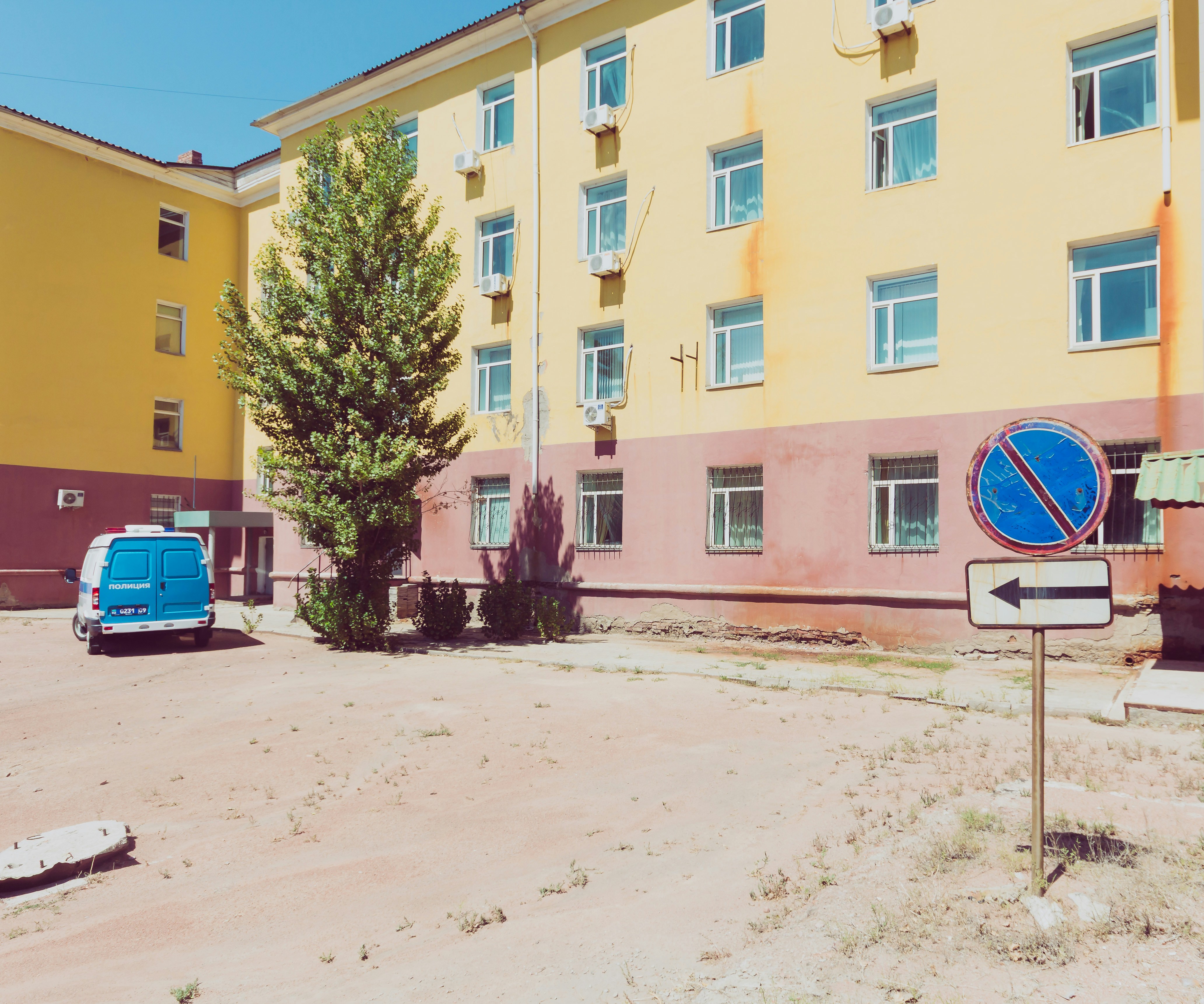 Sunlit courtyard with pastel apartment block and vintage van