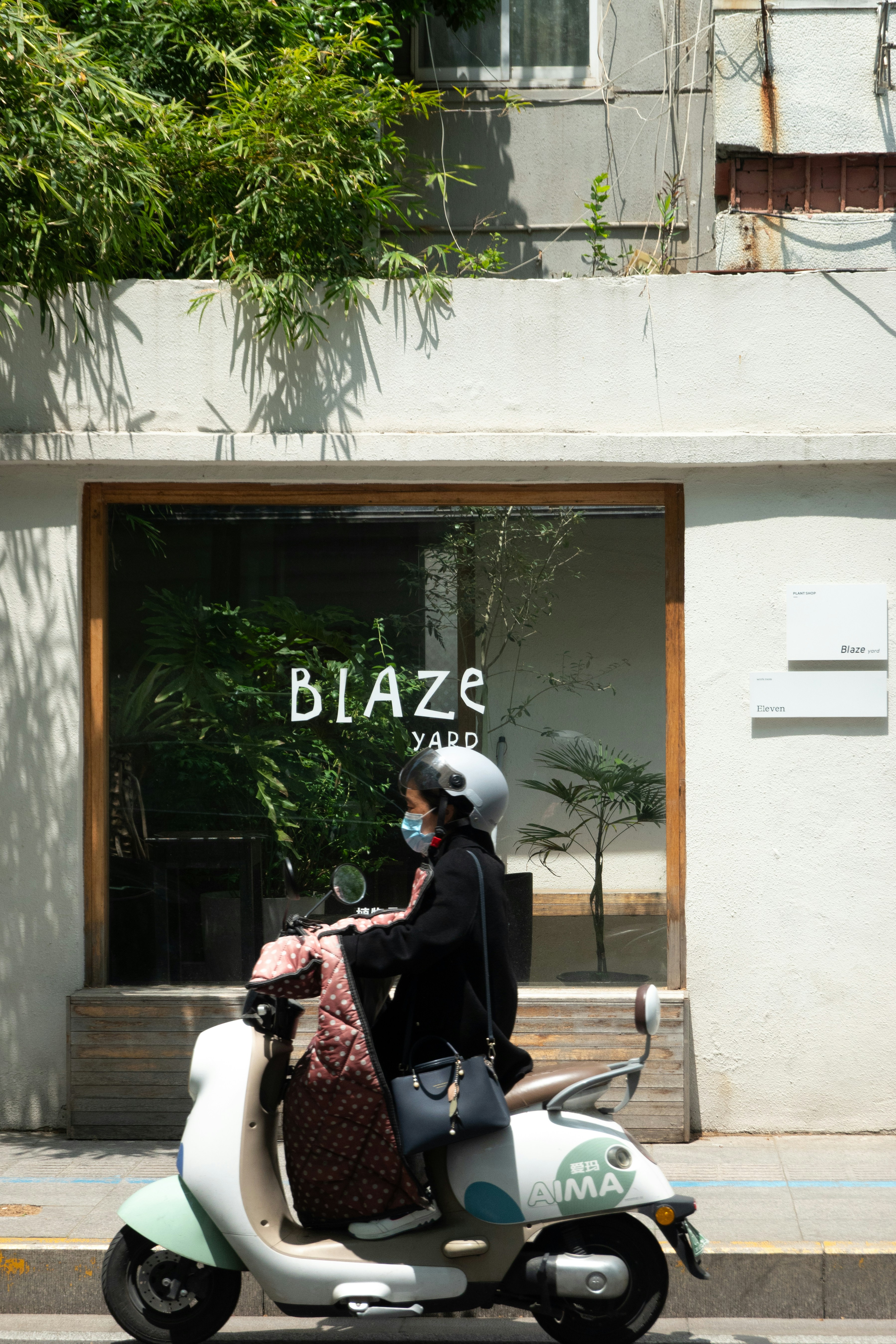 Urban Ride: Masked Commuter on a Mint Vespa in Front of a Boutique Window