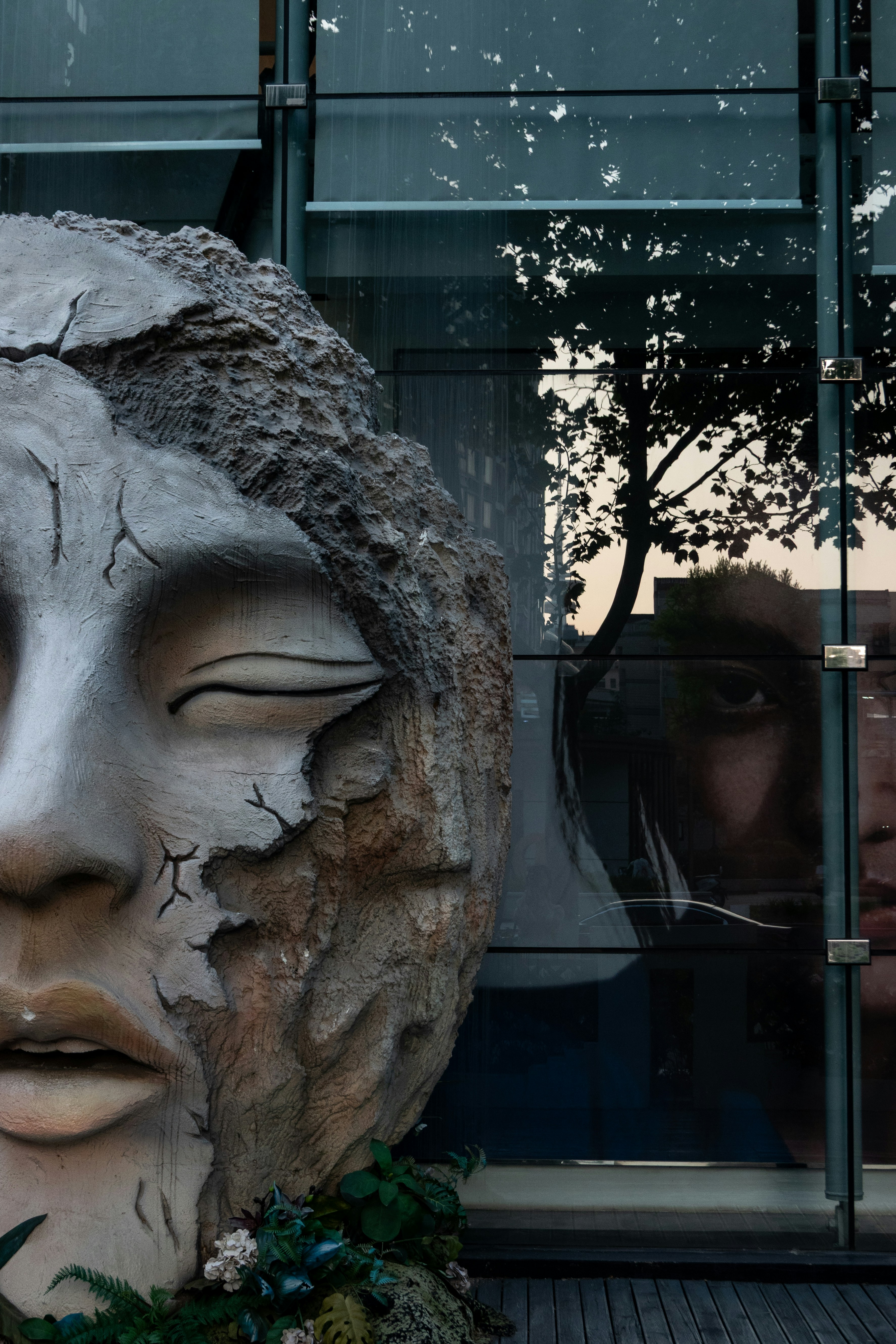 Cracked Serenity: Half-Face Statue Meets Reflected Window