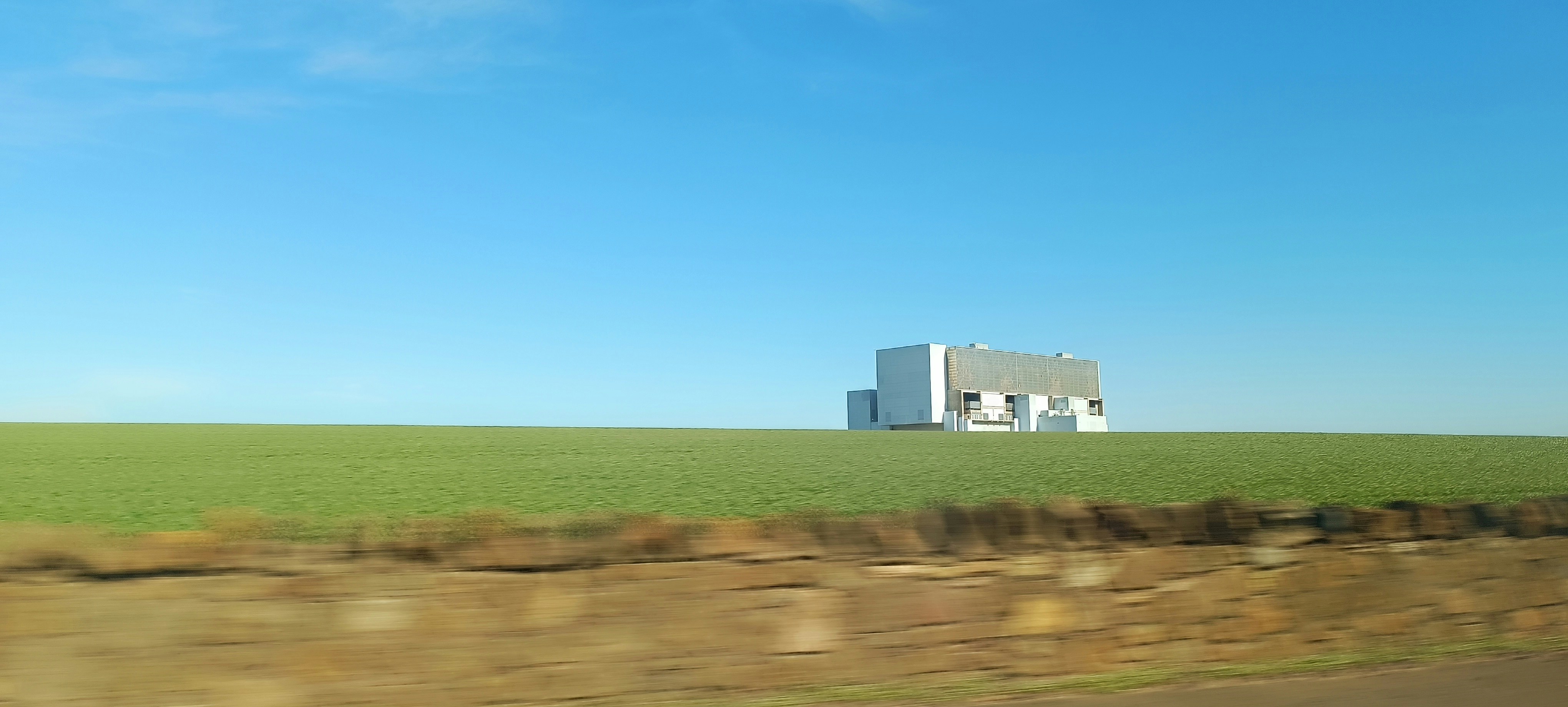 A lone barn-like structure on a windswept horizon