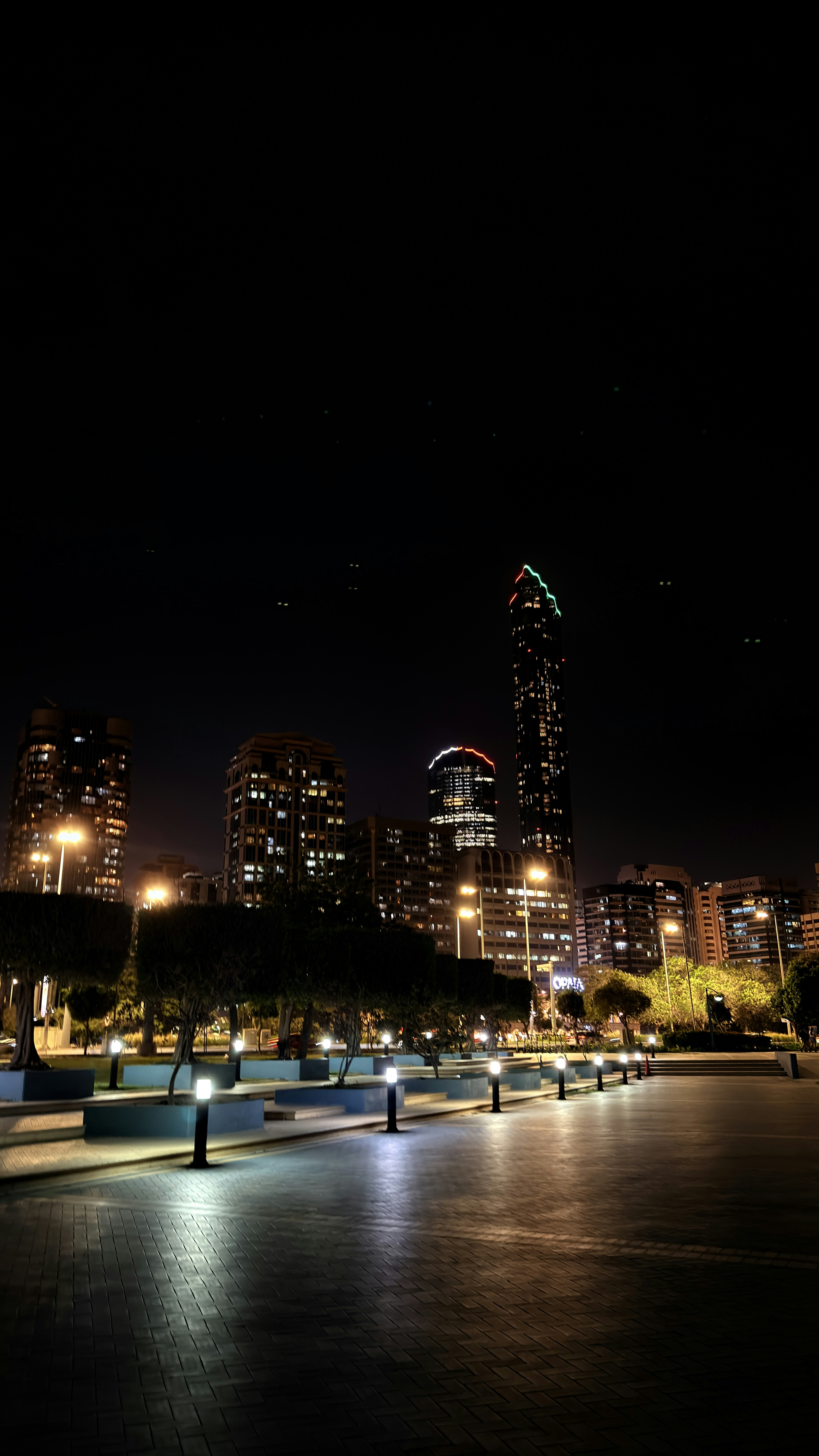 Midnight Skyline: Illuminated Towers Over a Quiet Waterfront Plaza