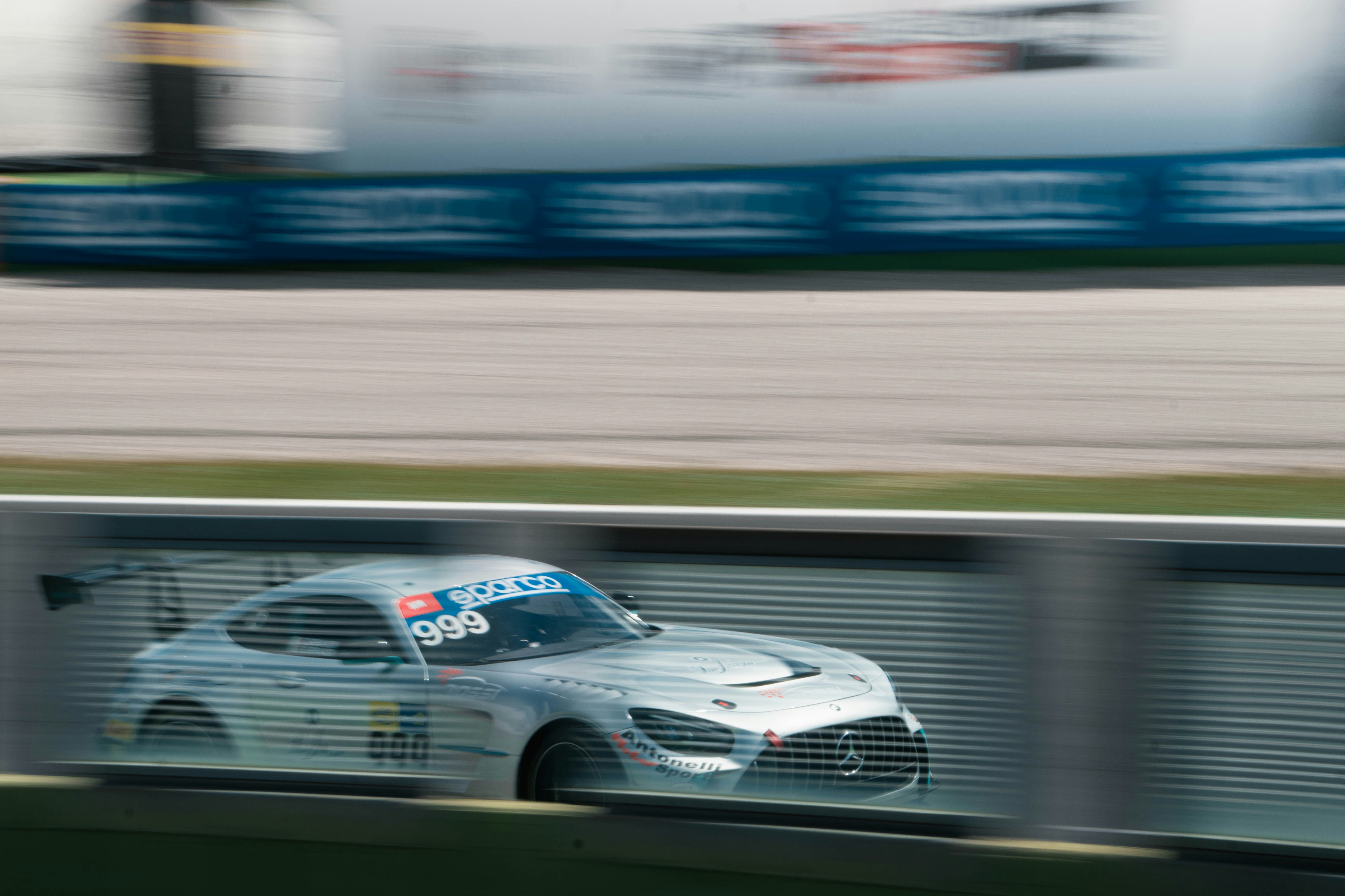 Silver Racing Mercedes Burst Through a Blurred Barrier