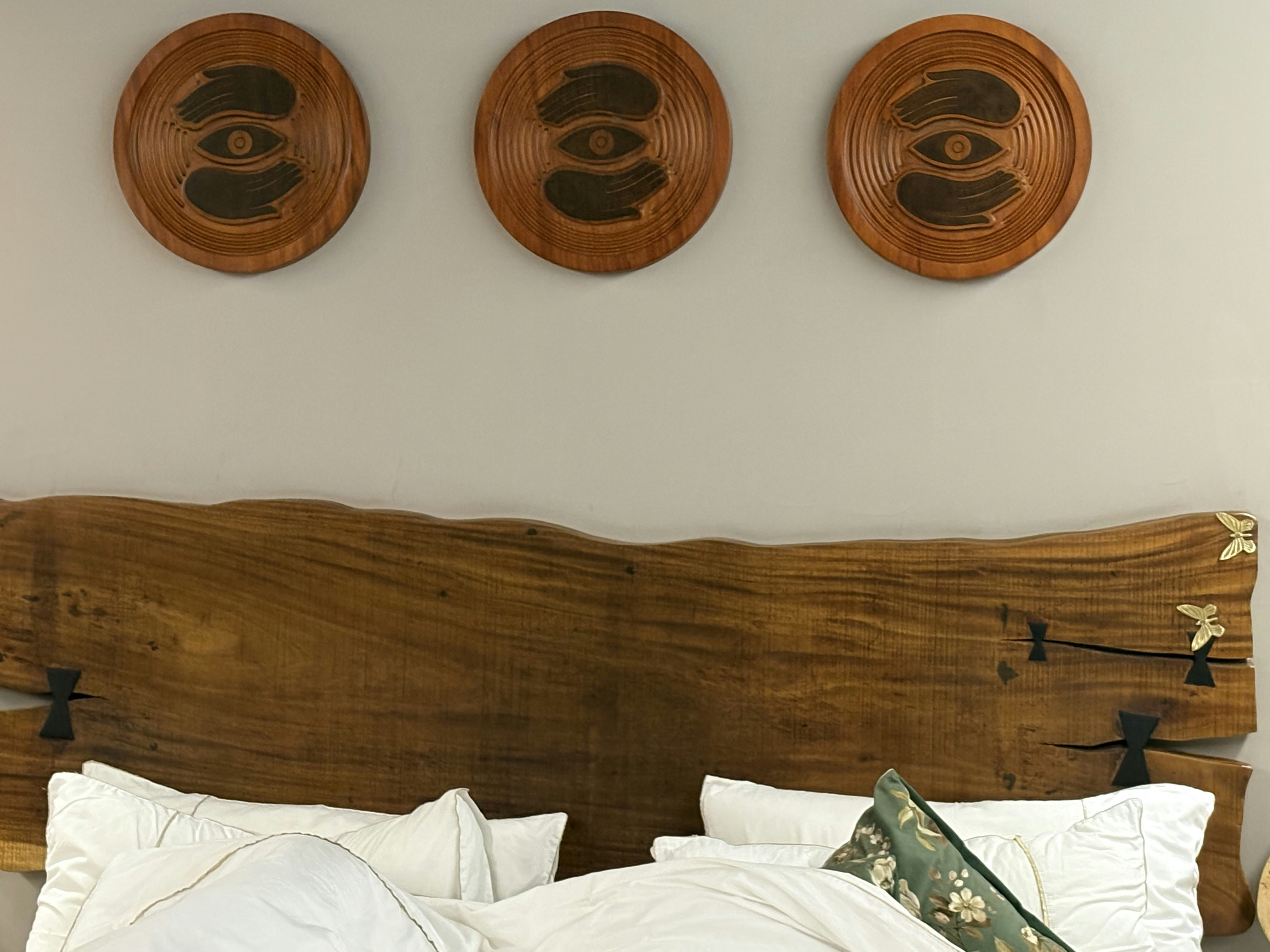 Carved headboard lullaby: three circular wall plaques above a rustic bed