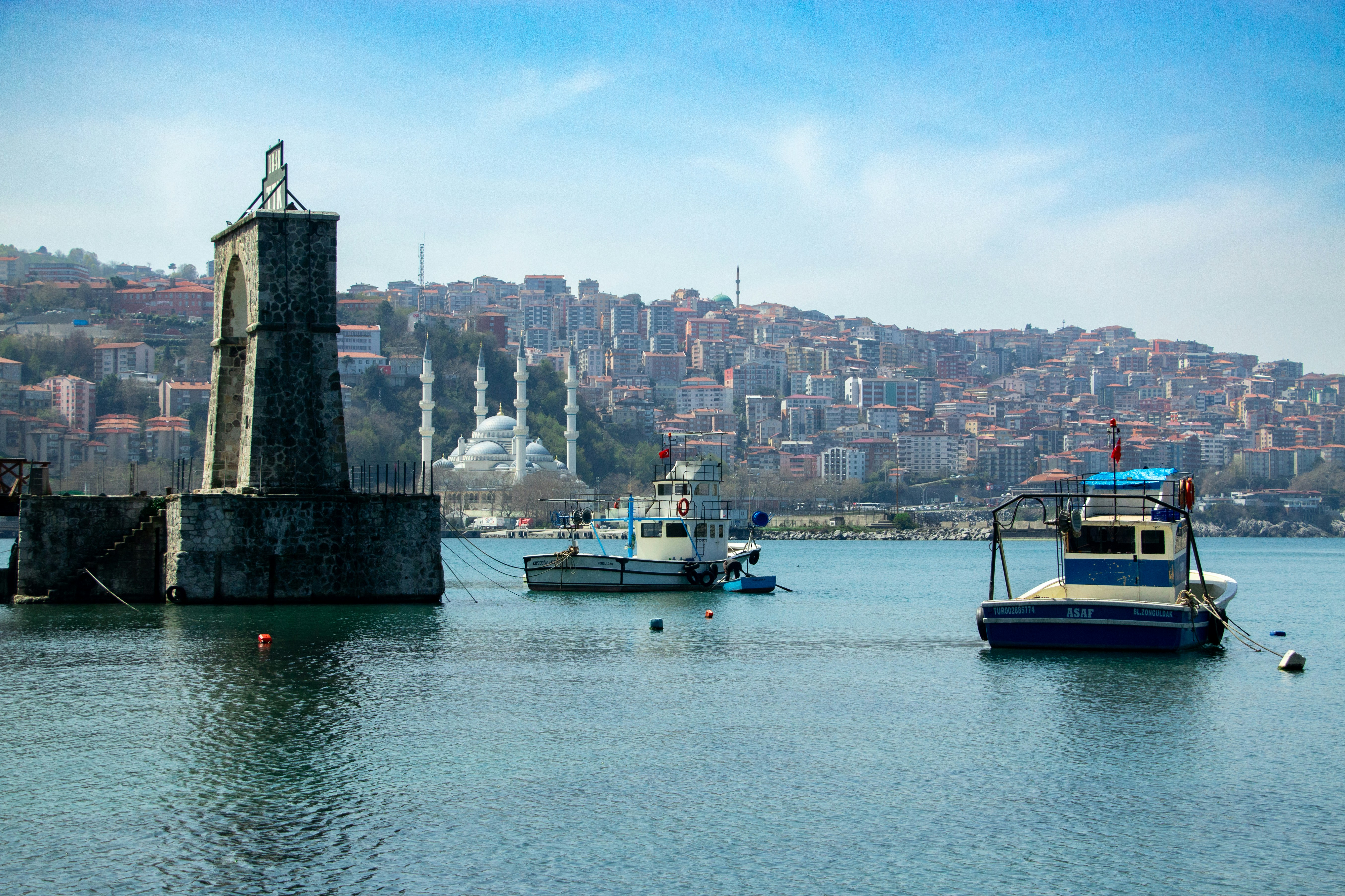 Harbor Sentinel: A Stone Pier with Boats and a City Cresting the Bay