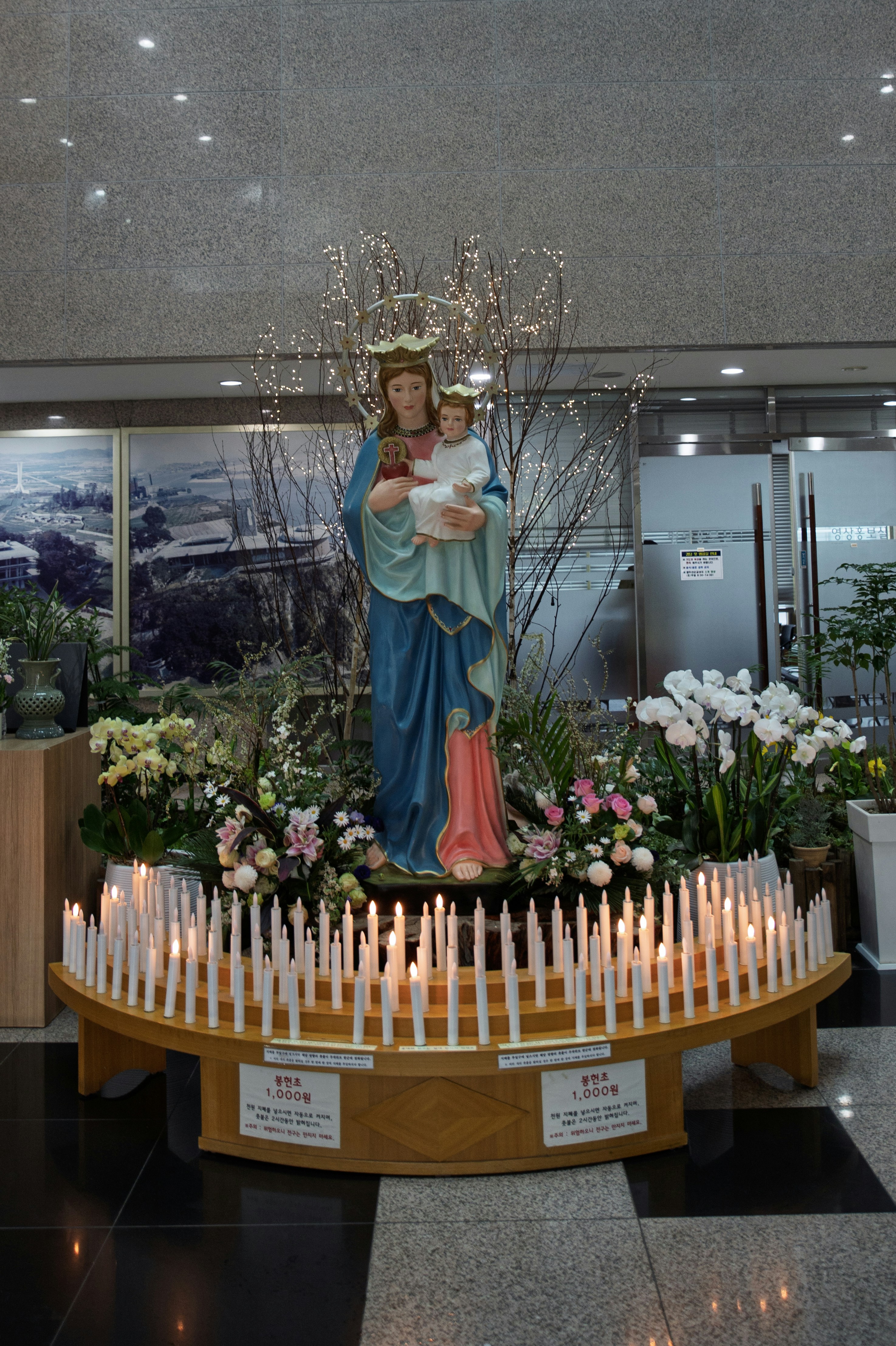 Statue of Mary with Child at a Candlelit Shrine in an Indoor Lobby