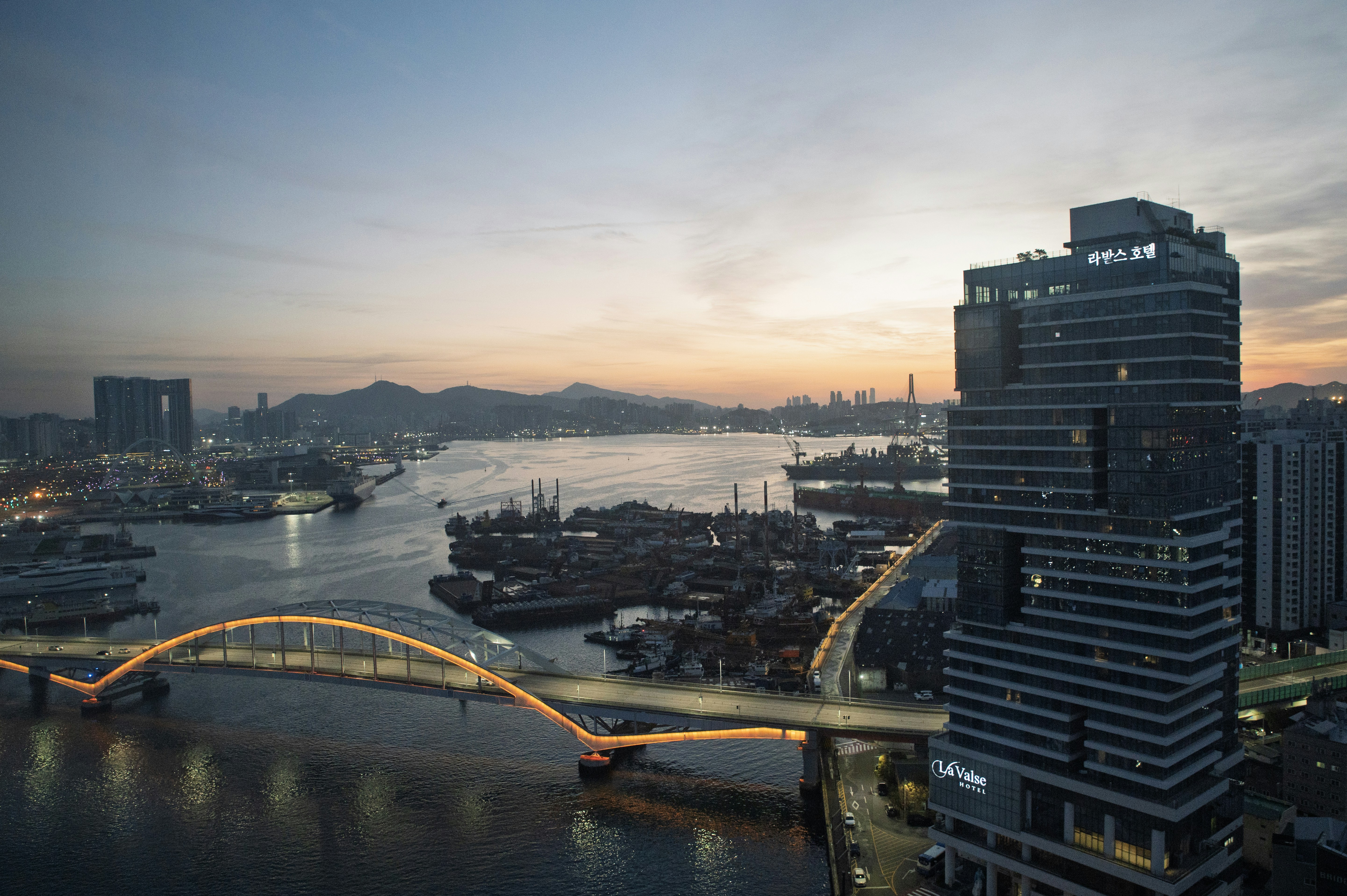 Golden Arc over the River: A Modern Harbor at Dusk