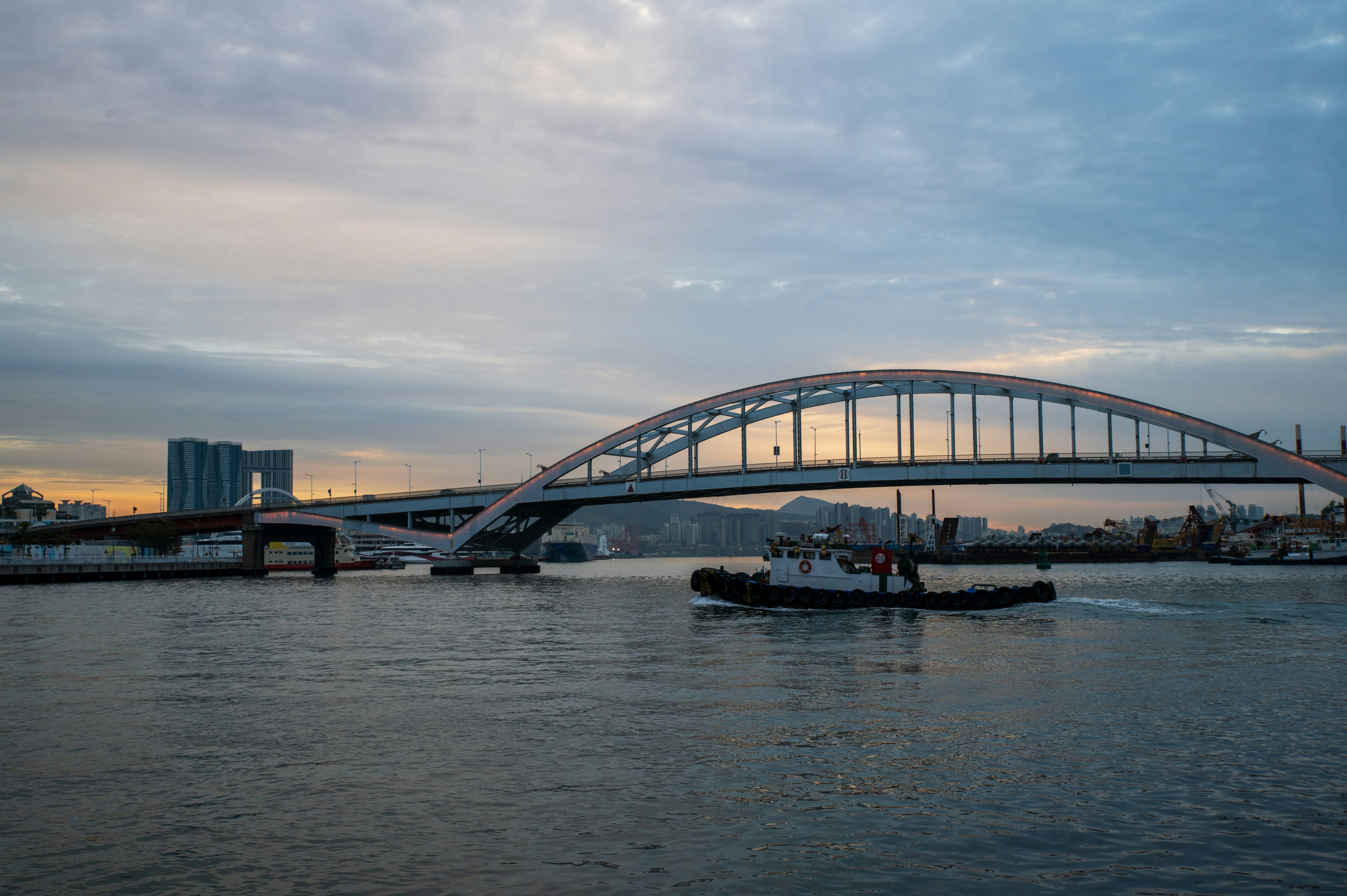 Sunlit Arch Over a Calm River: Cityscape at Dusk