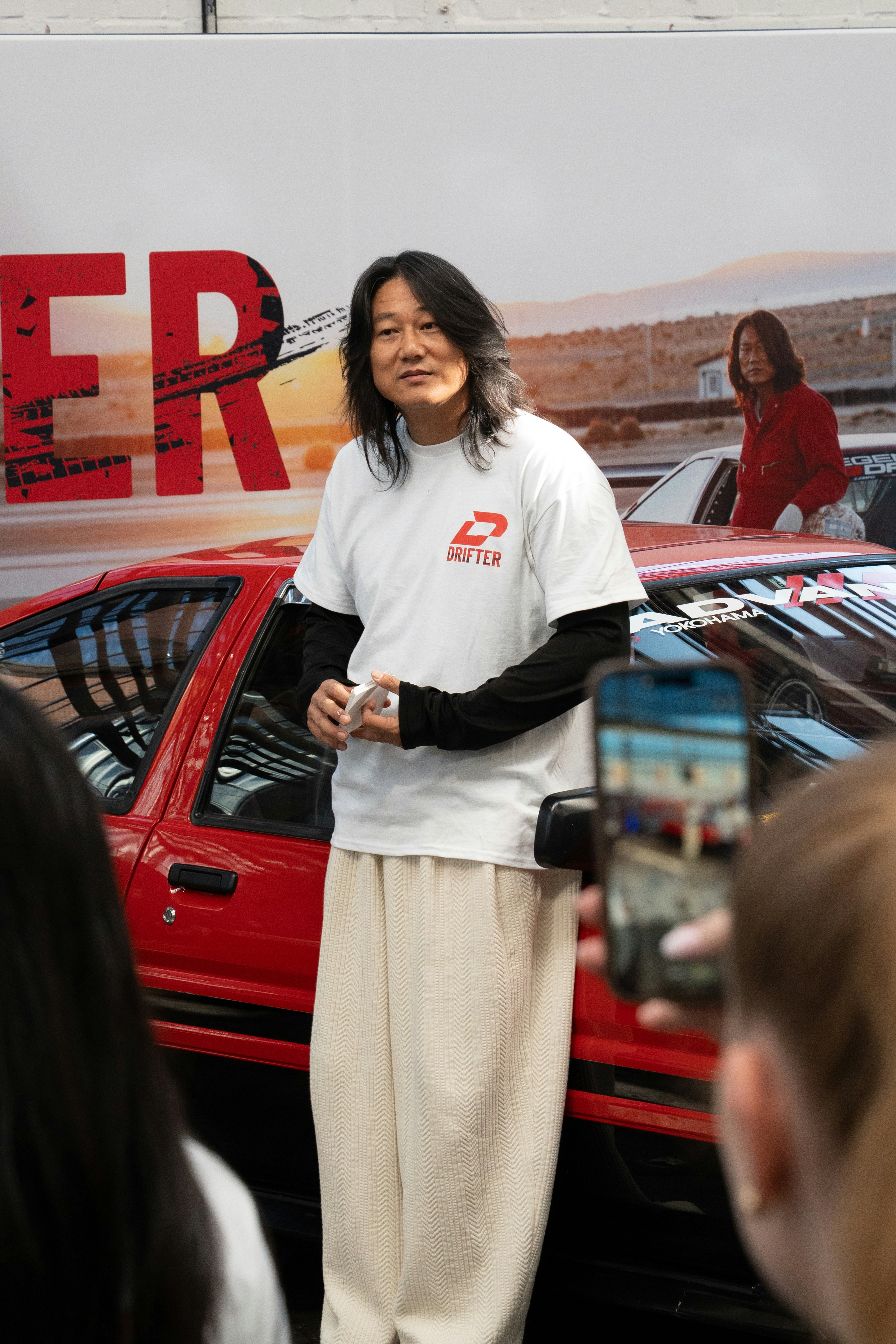 Former racing scene come to life: a presenter in front of a red classic in a car show