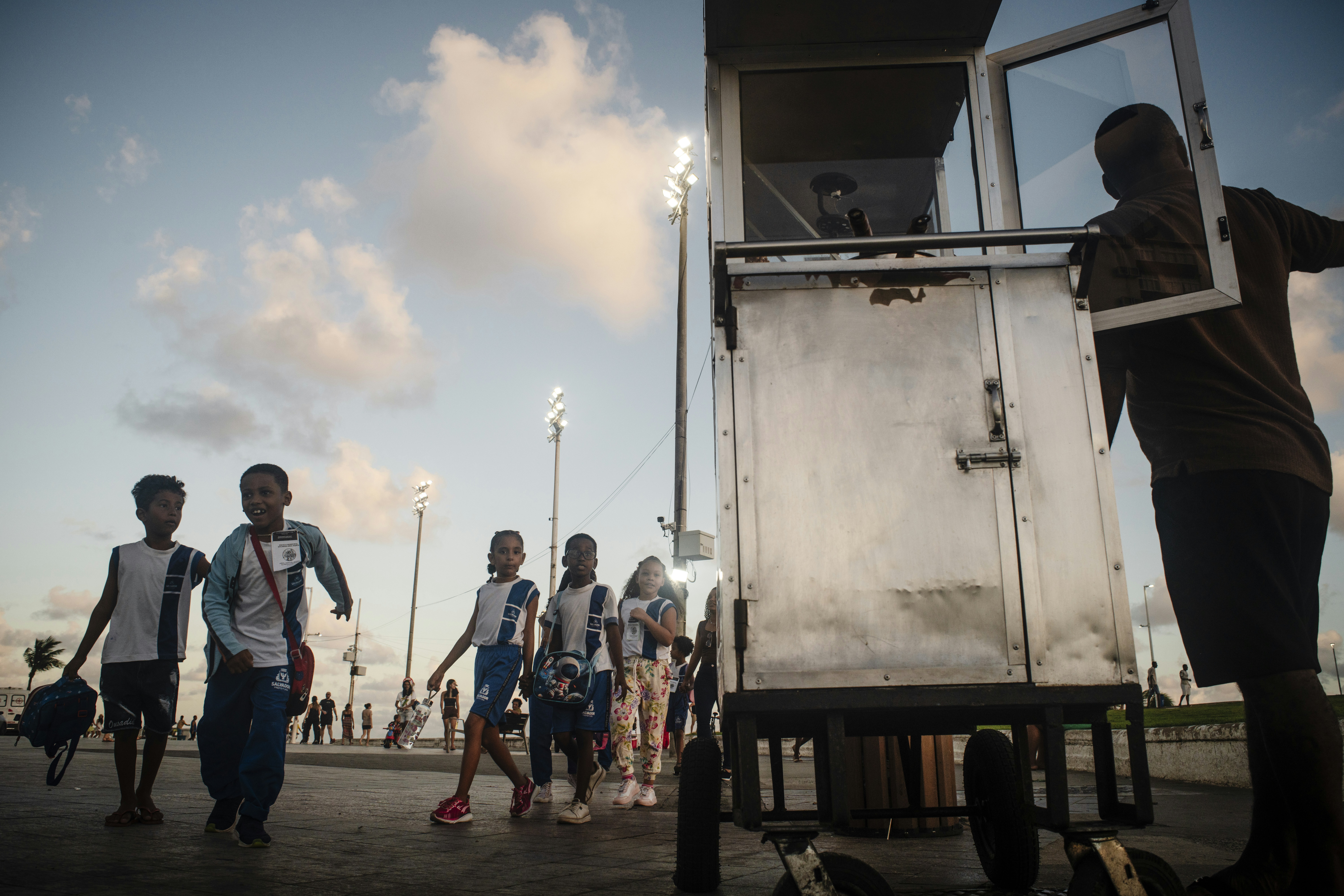 Children walk past a guard booth at dusk.