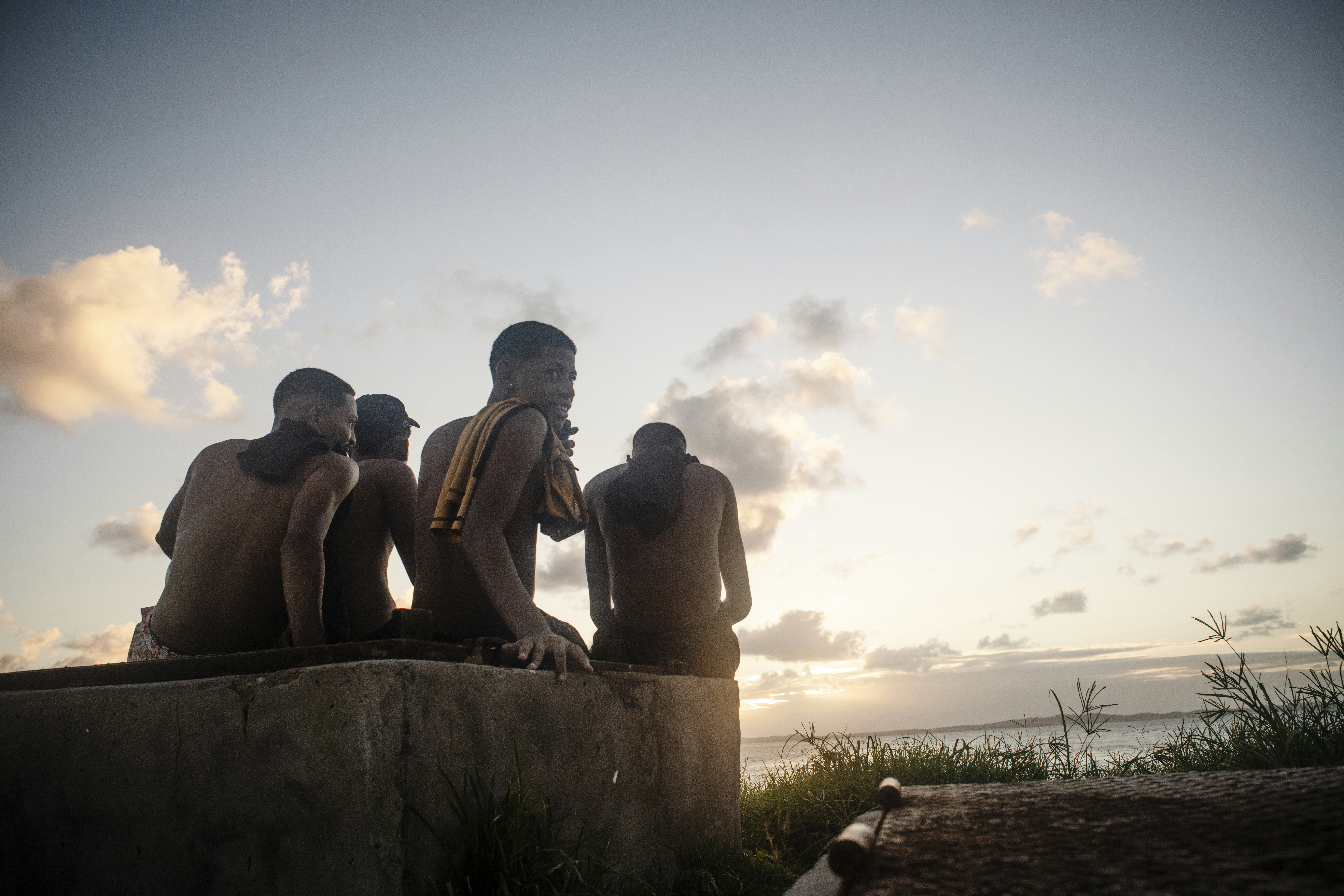 Four people sit on a wall watching the sunset.