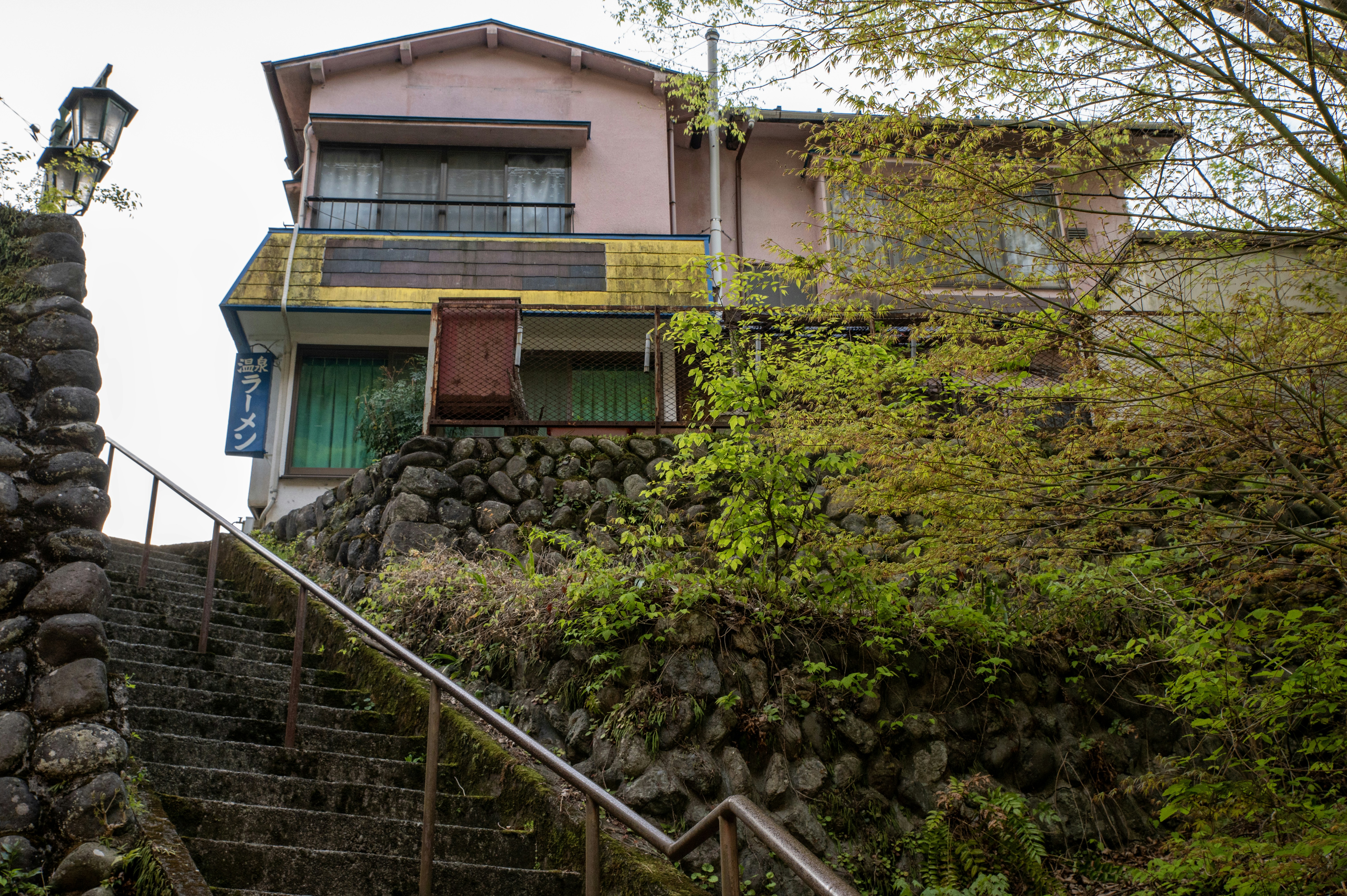 Pink hillside home peeking over ancient stonework at leafy bend