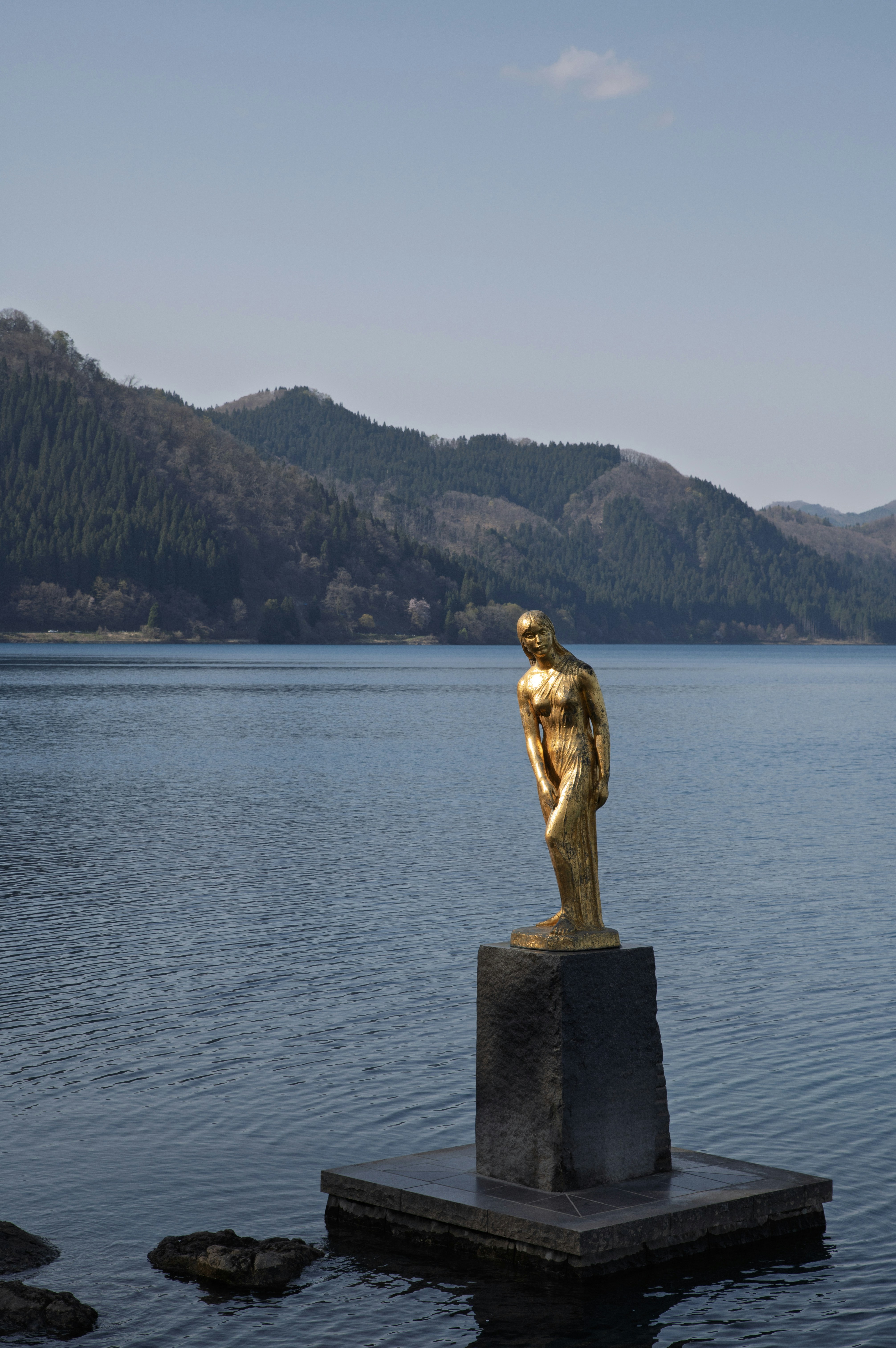 Golden Statue on a Quiet Lake: Morning Light on a Waterside Veritas