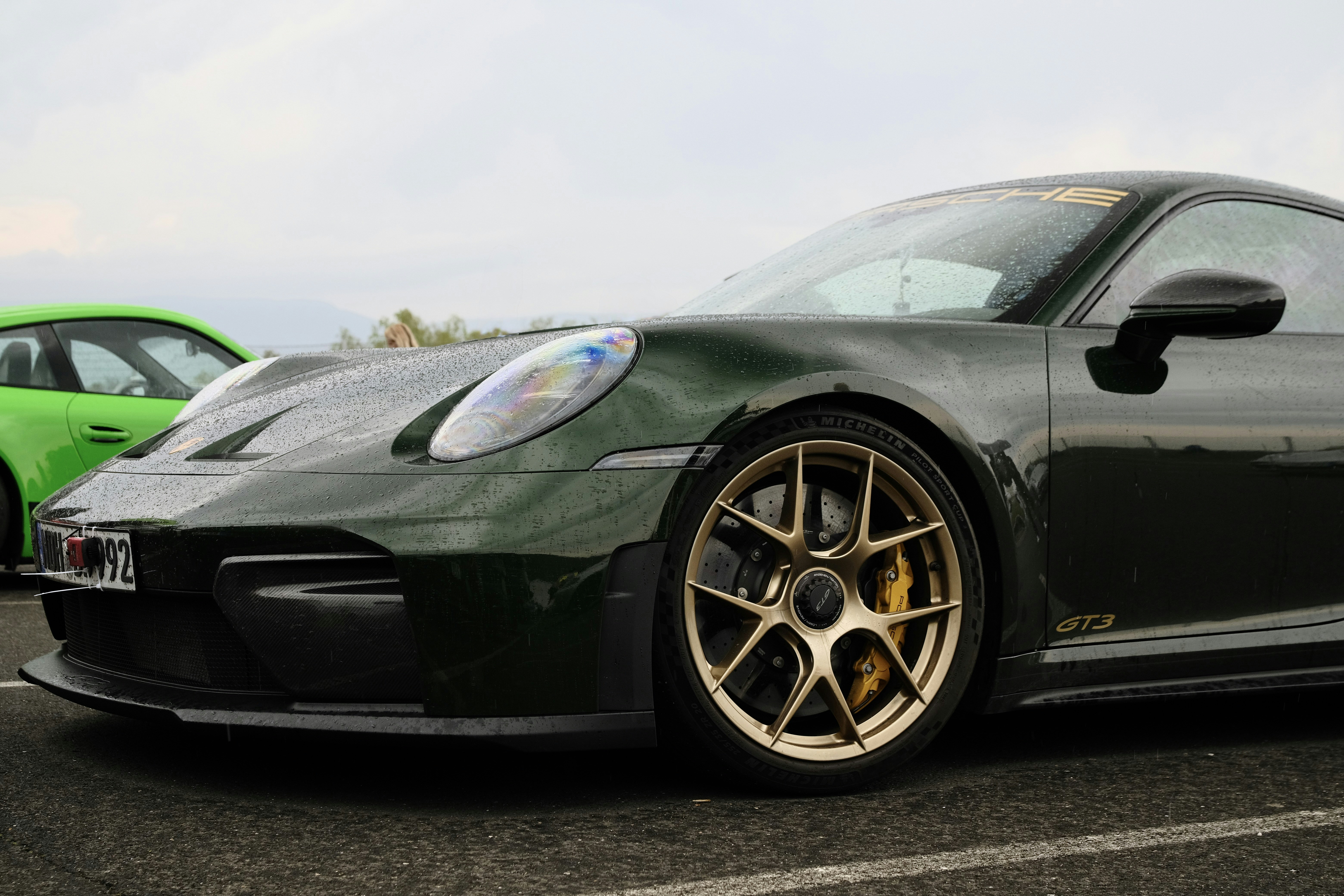Low-angle Porsche silhouette: gold calipers and green rival